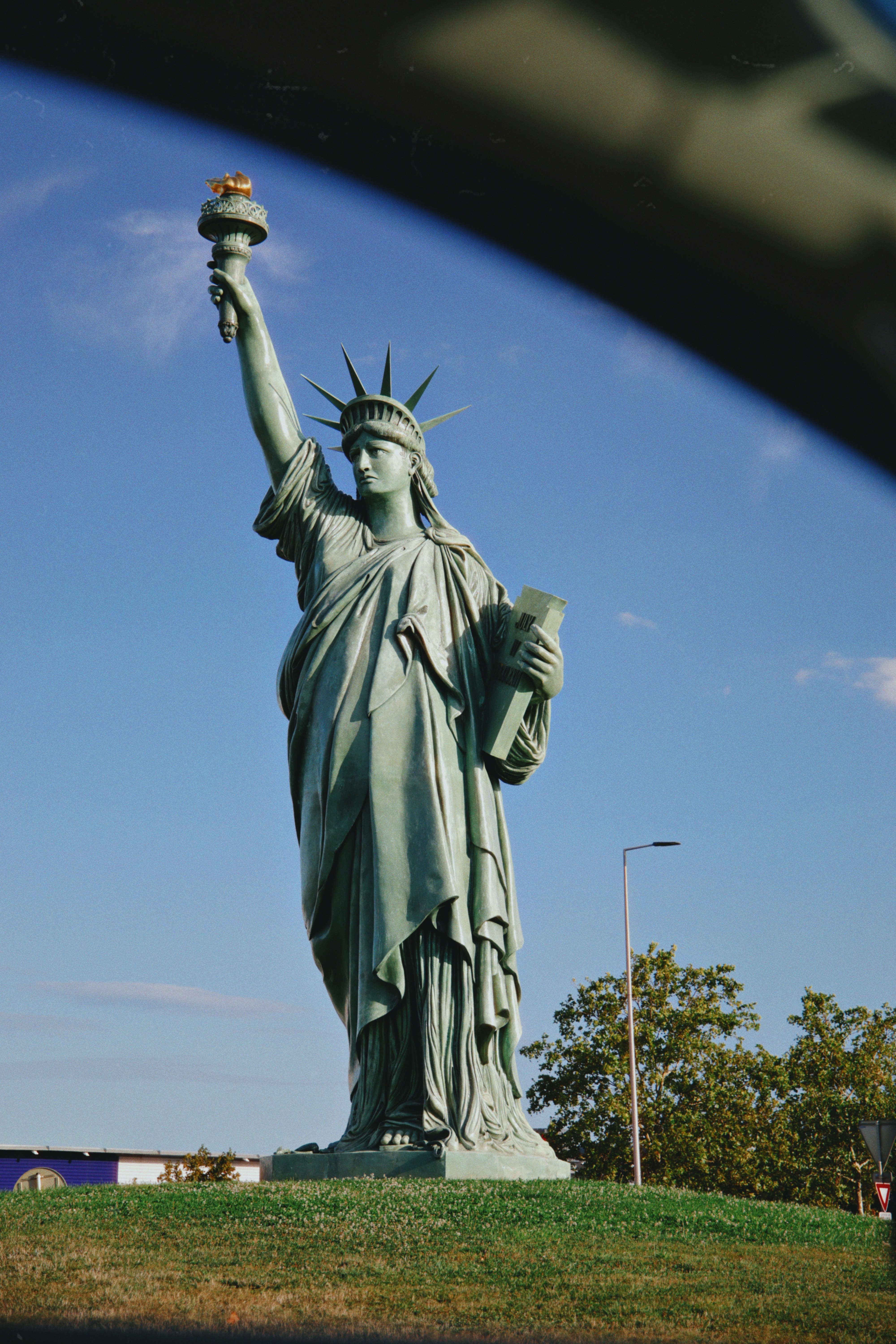 Statue of Liberty portrait framed by a curved car windshield