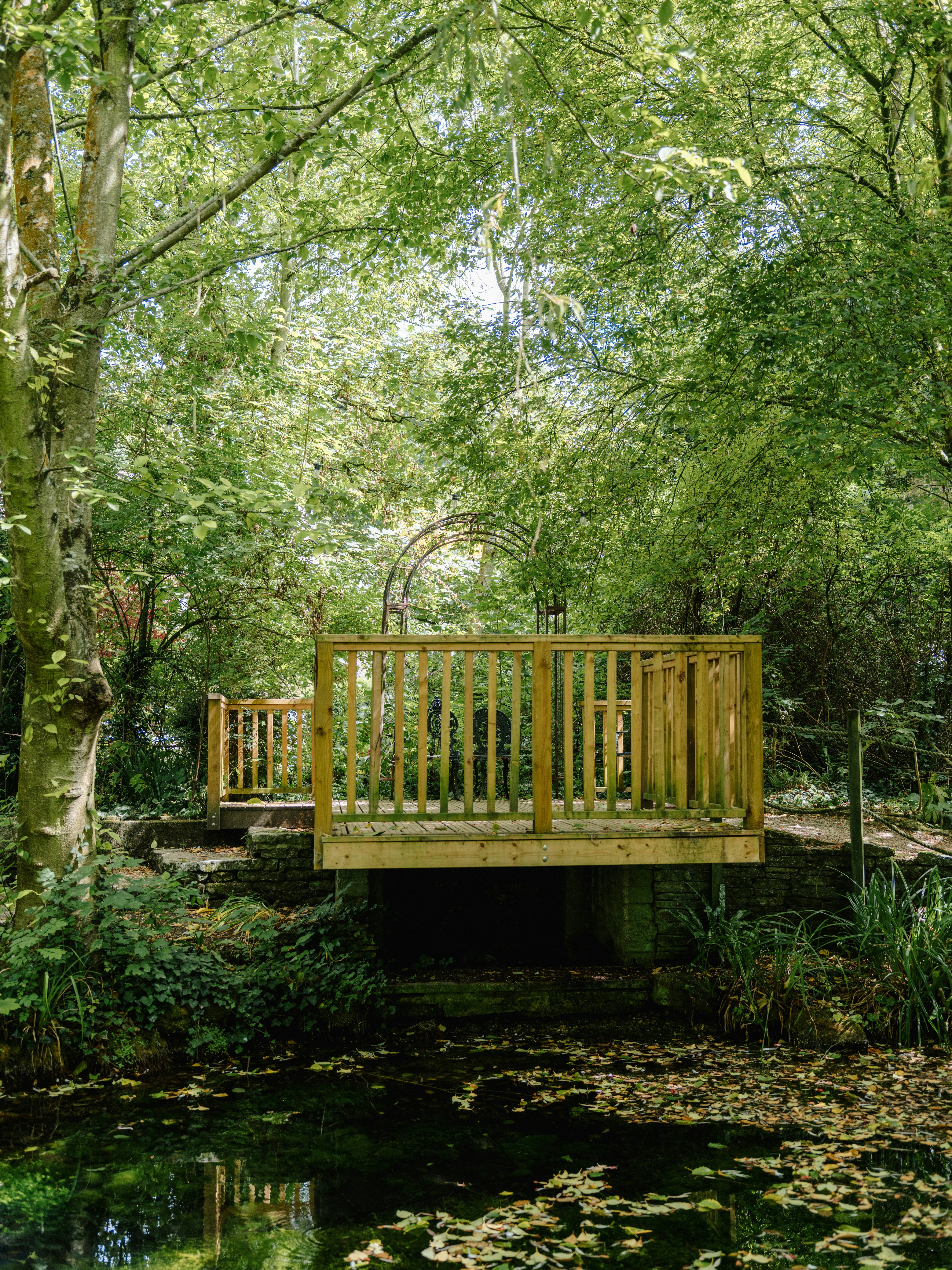 Wooden Deck Overlooking a Quiet Stream in a Lush Green Garden