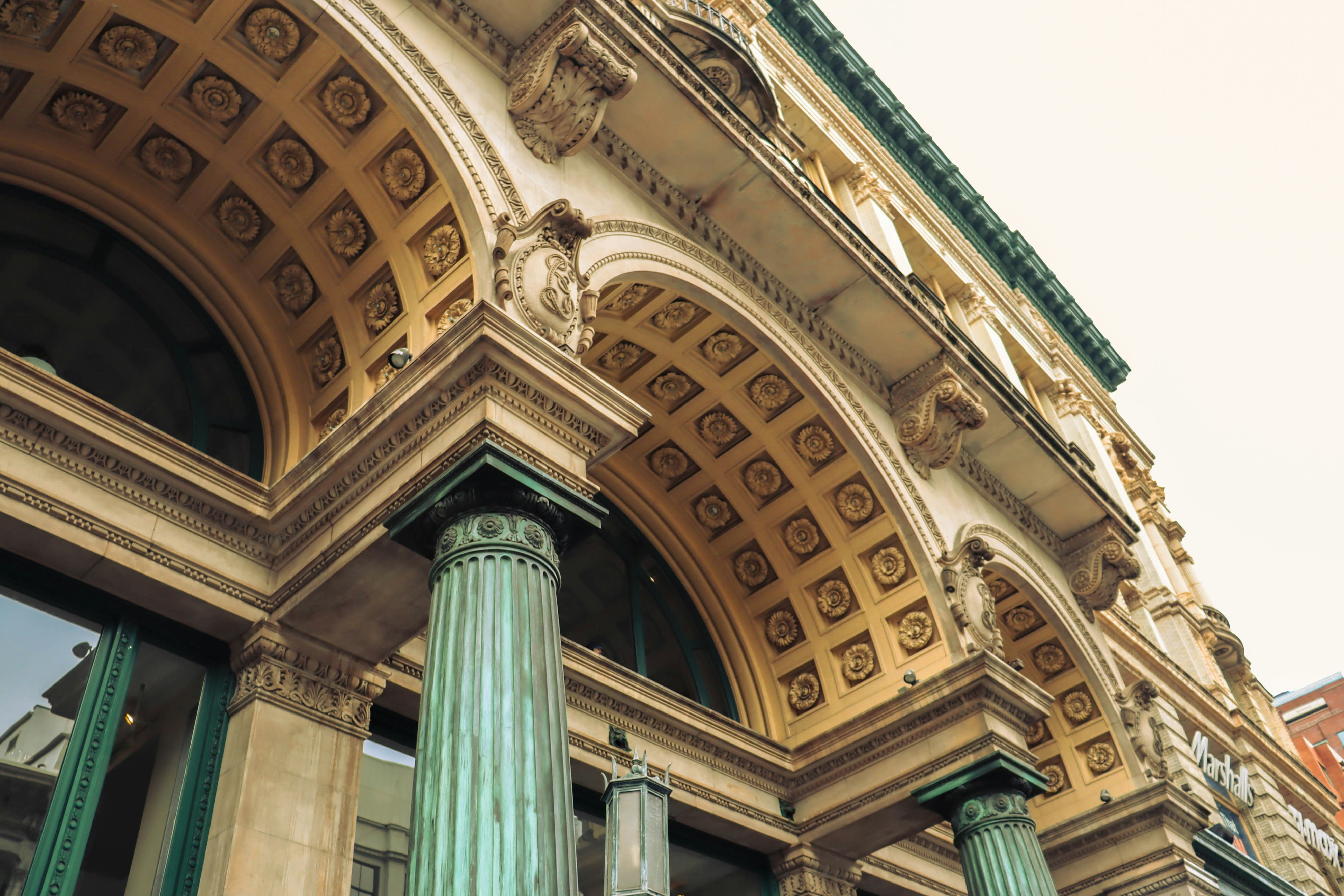 Architectural detail featuring an arched facade with decorative coffers and green marble columns in soft morning light.