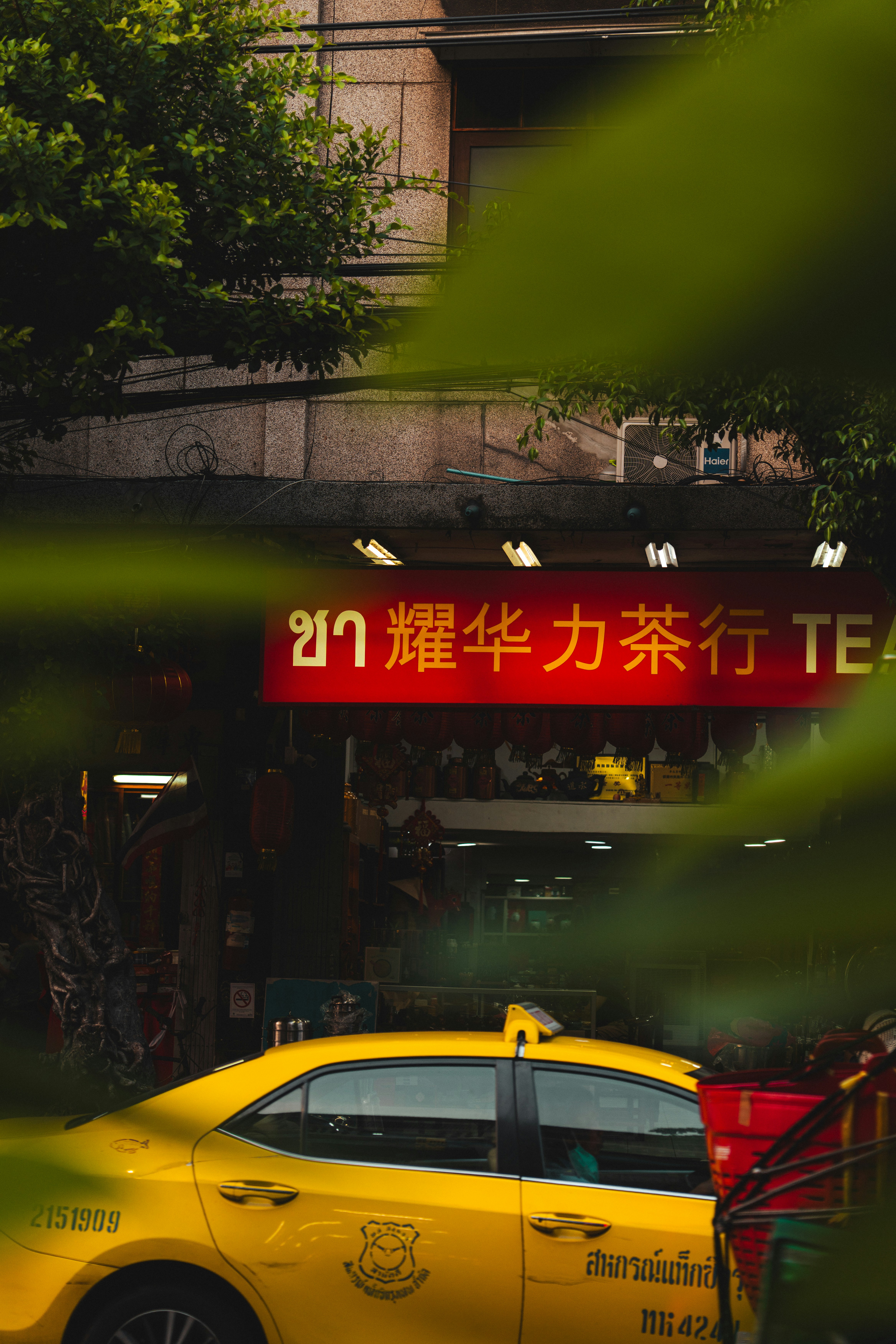 Yellow Taxi at a Street Corner Framed by Green Fronds