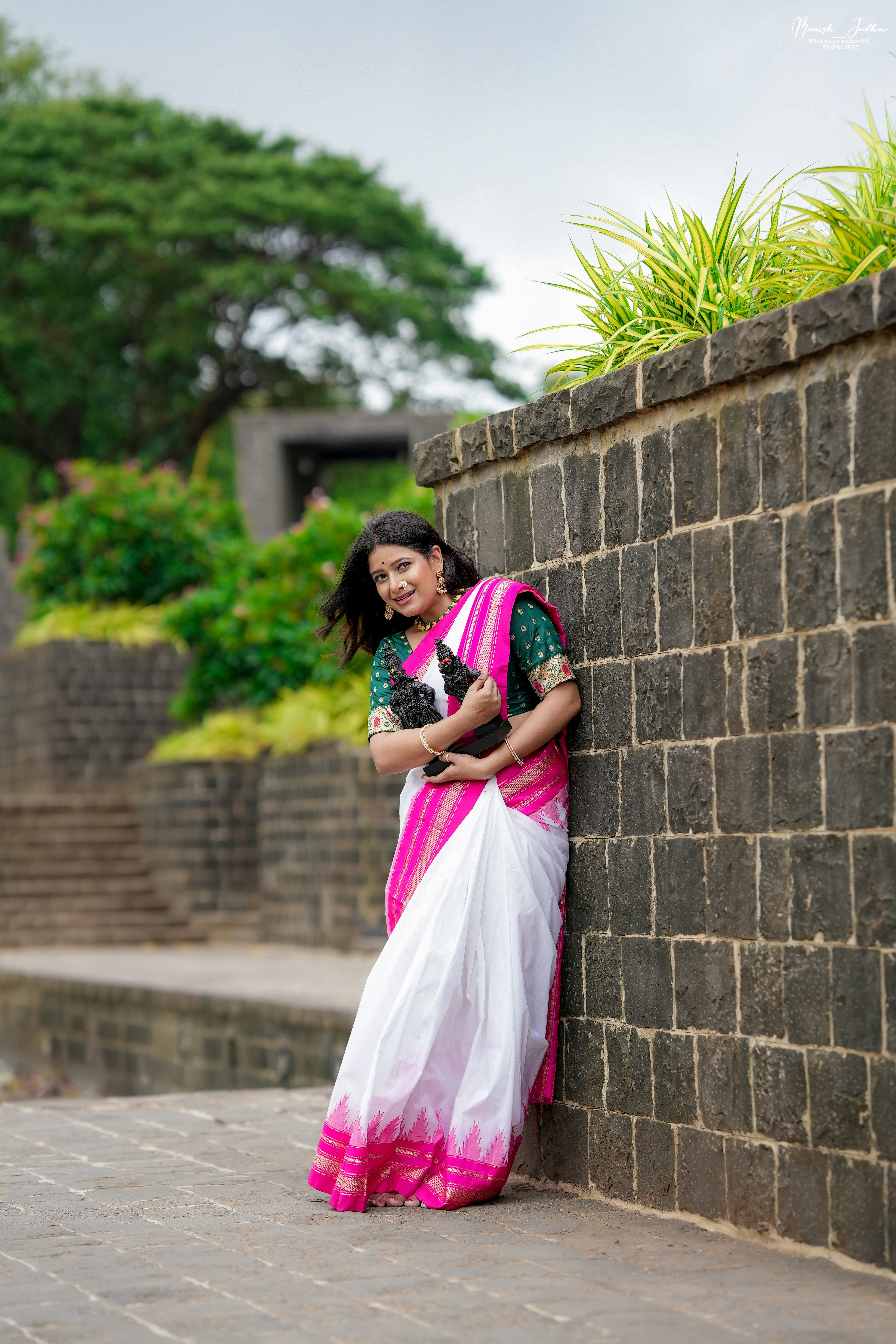 Sari-clad figure leaning from a stone wall