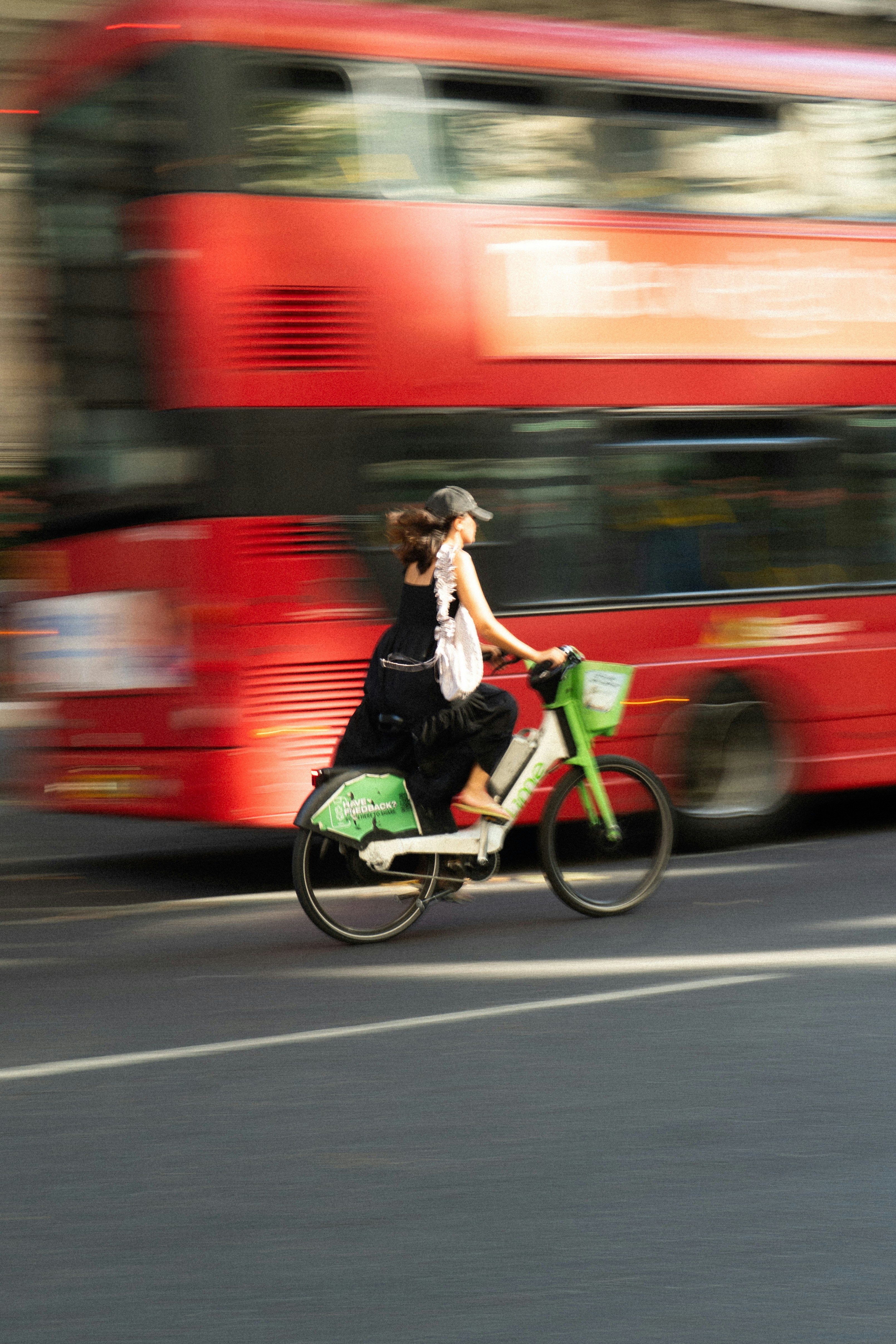Motion in the City: Rider in a Green Spark on a Blurred Red Bus Backdrop
