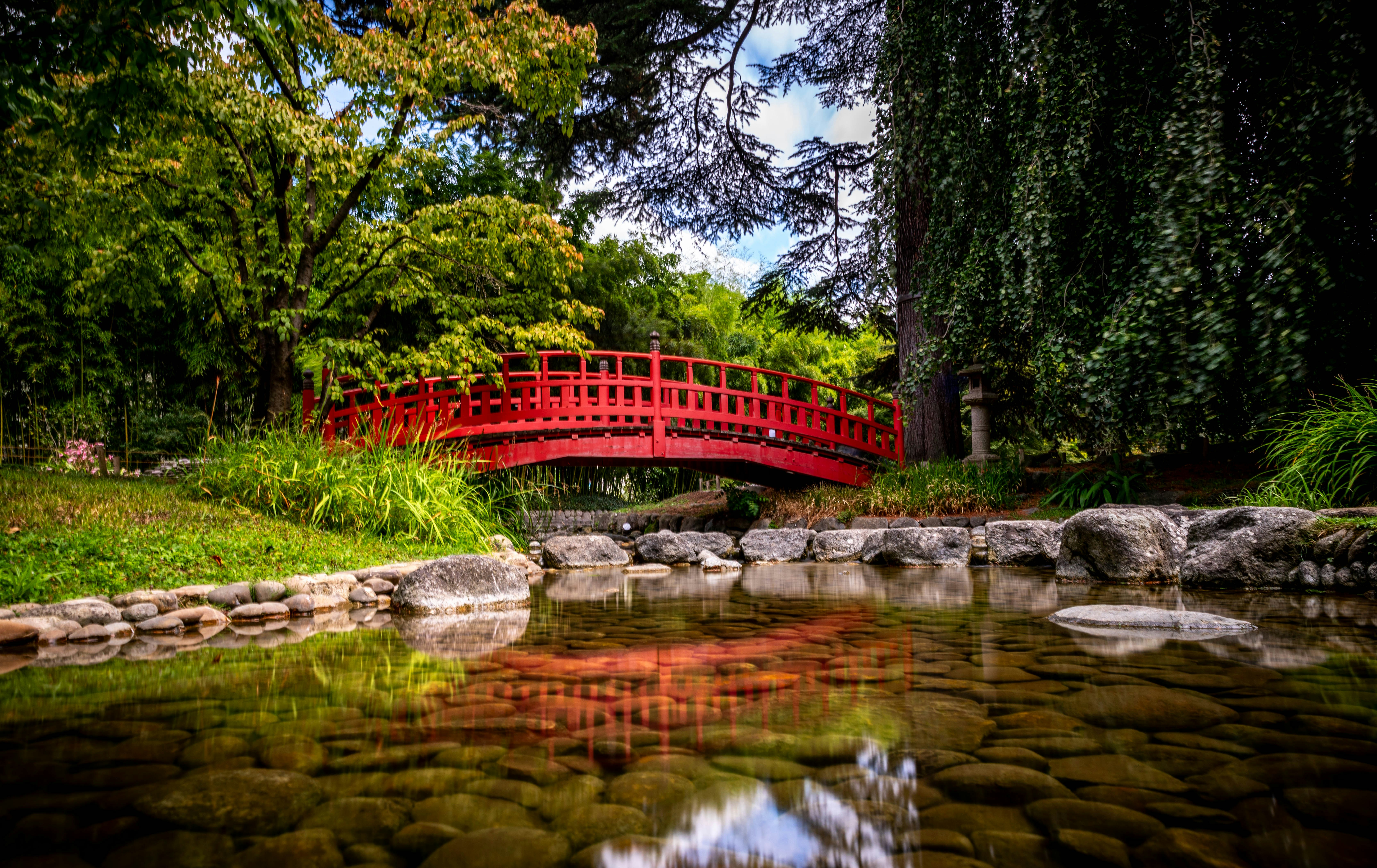 Red Crossing: A Tranquil Bridge over a Pebbled Stream