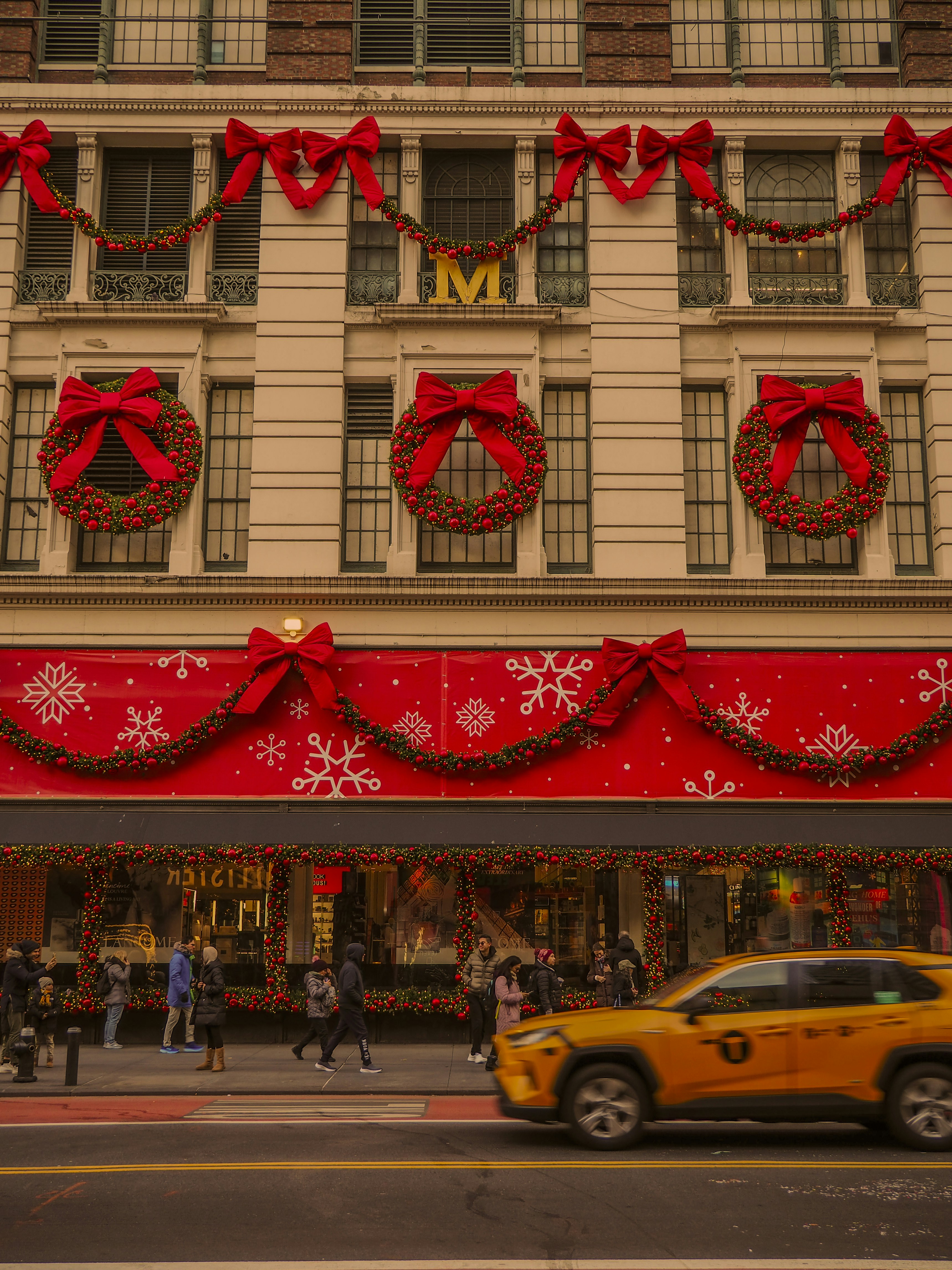 Festive Facade: Red Ribbons and Holiday Wreaths Adorn a City Street
