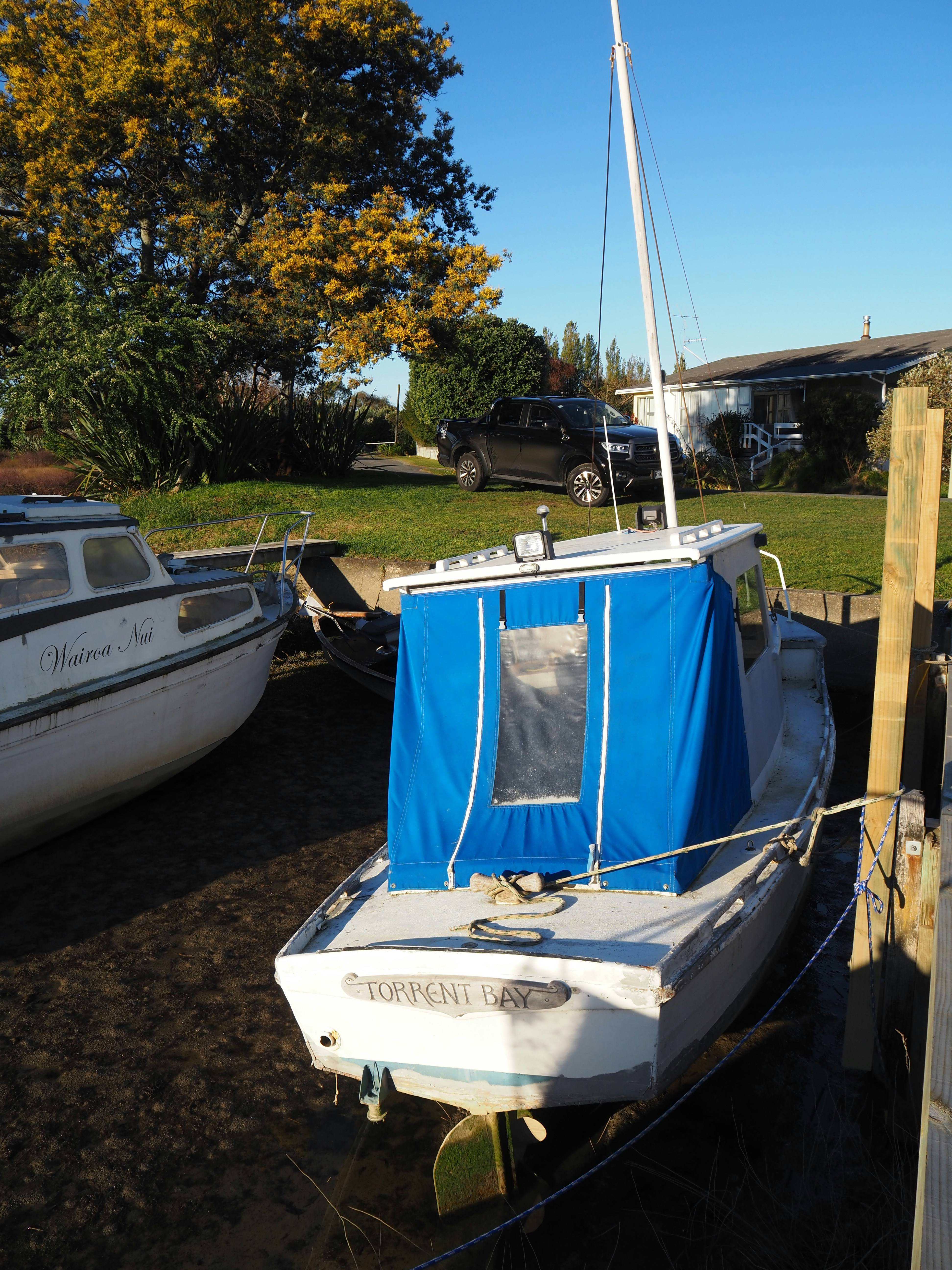 Blue-canvas sailboat at the marina under bright afternoon sun