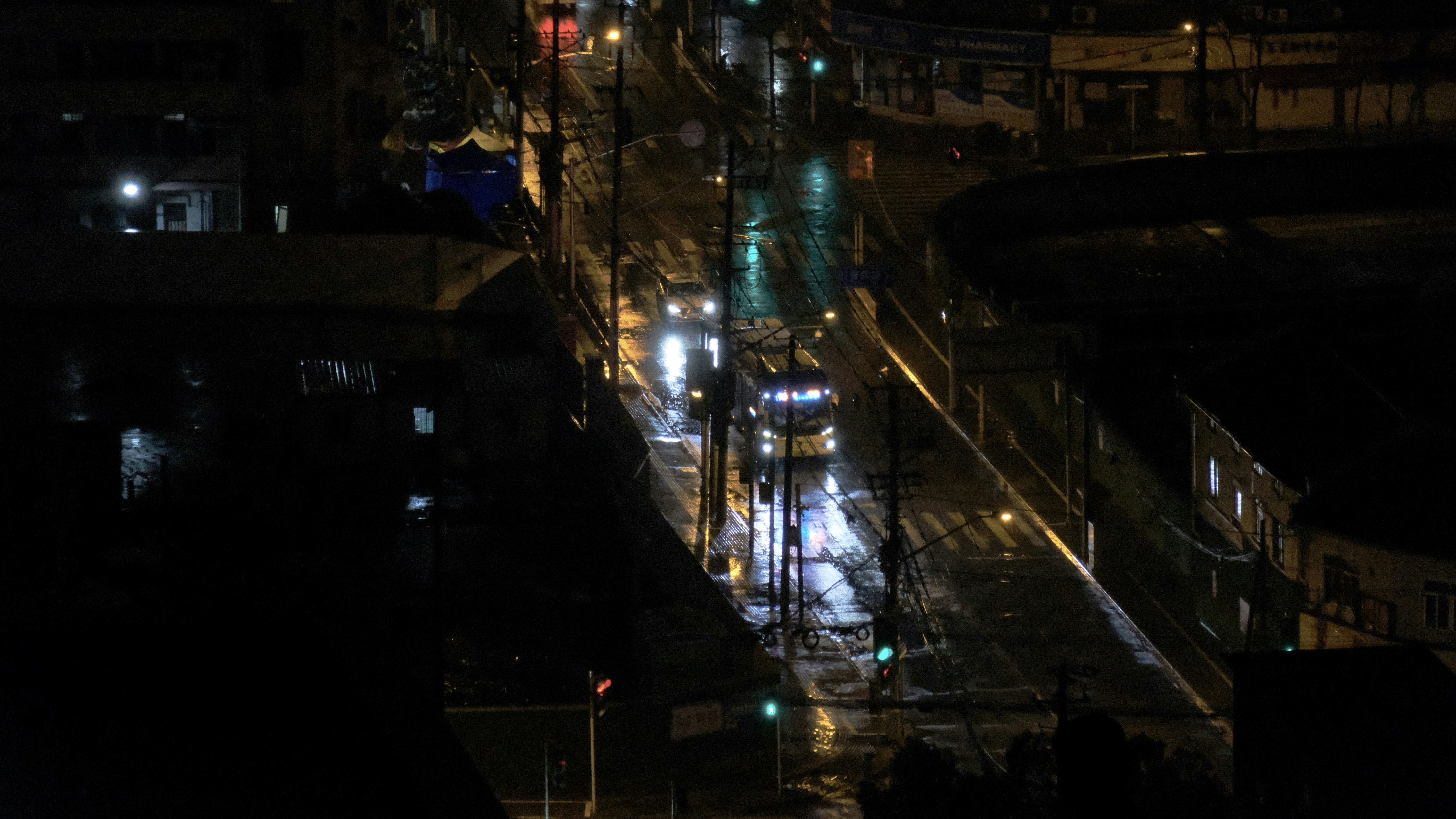 Rain-soaked arterial glow: a neon-lit city street after dusk