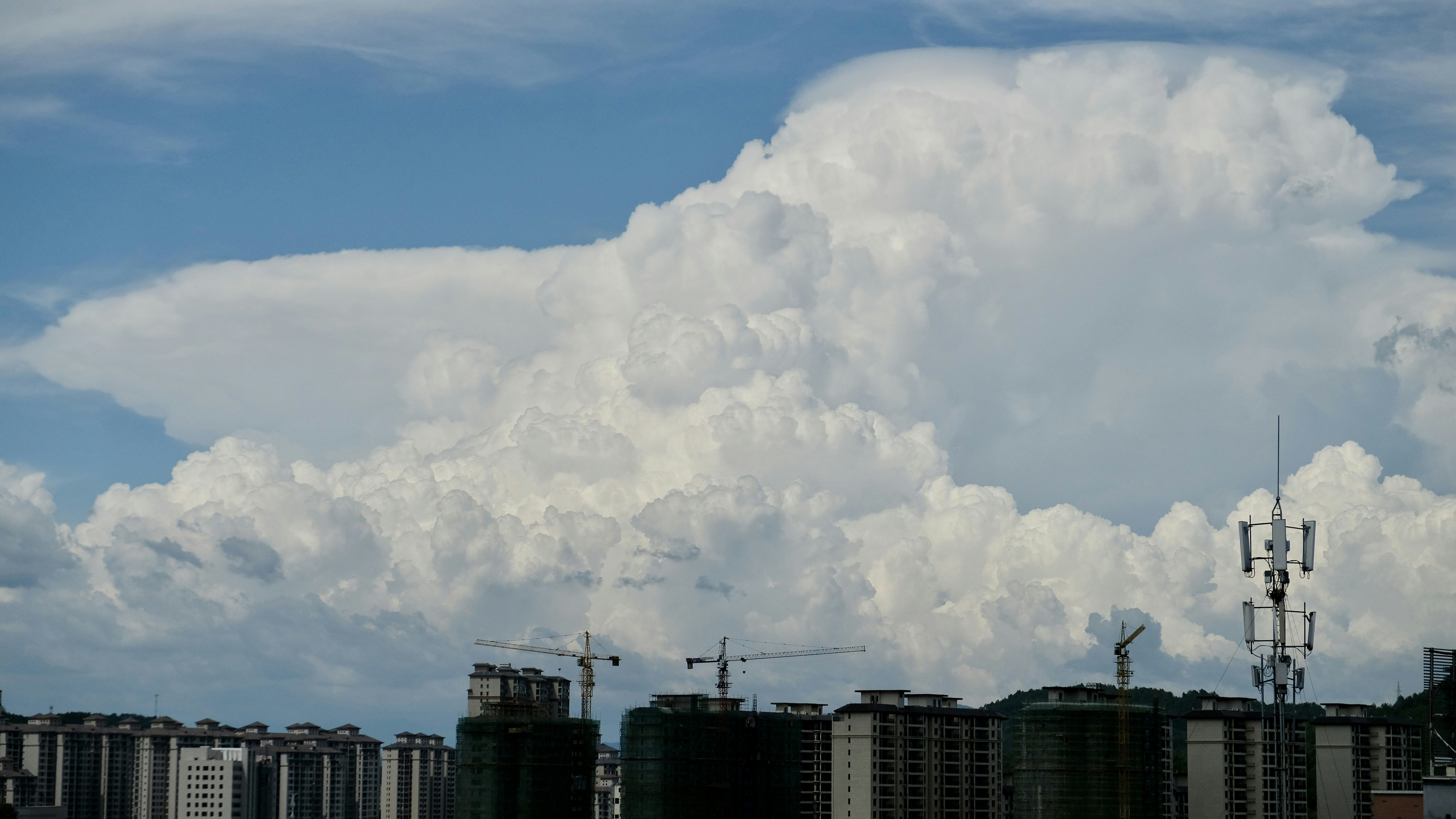 Cloud Giants Over the City Silk: Distant Skyline Under Broad Sky