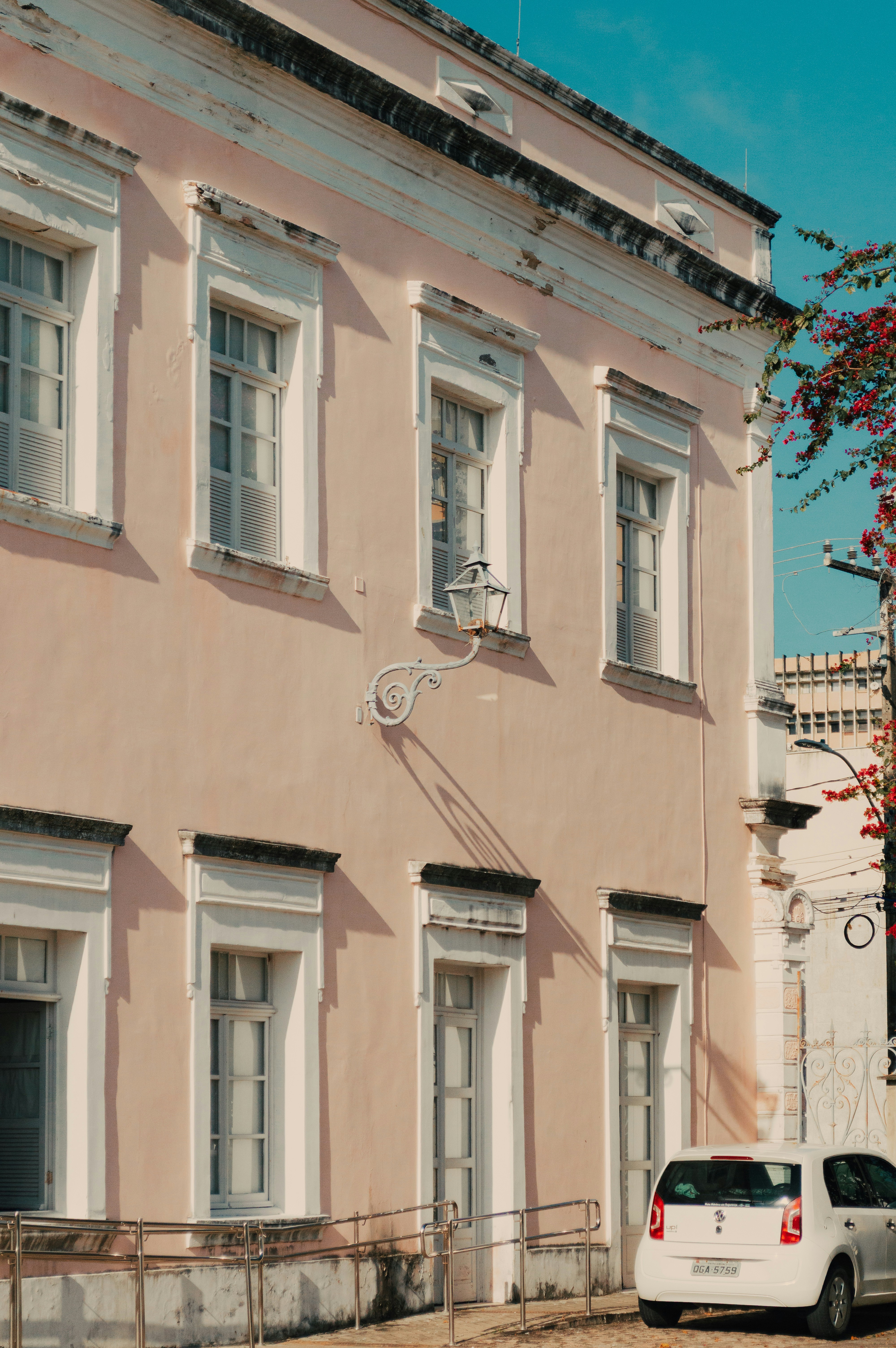 Sunlit Facade: A Pink Townhouse Eclipsed by Shade and a White Car