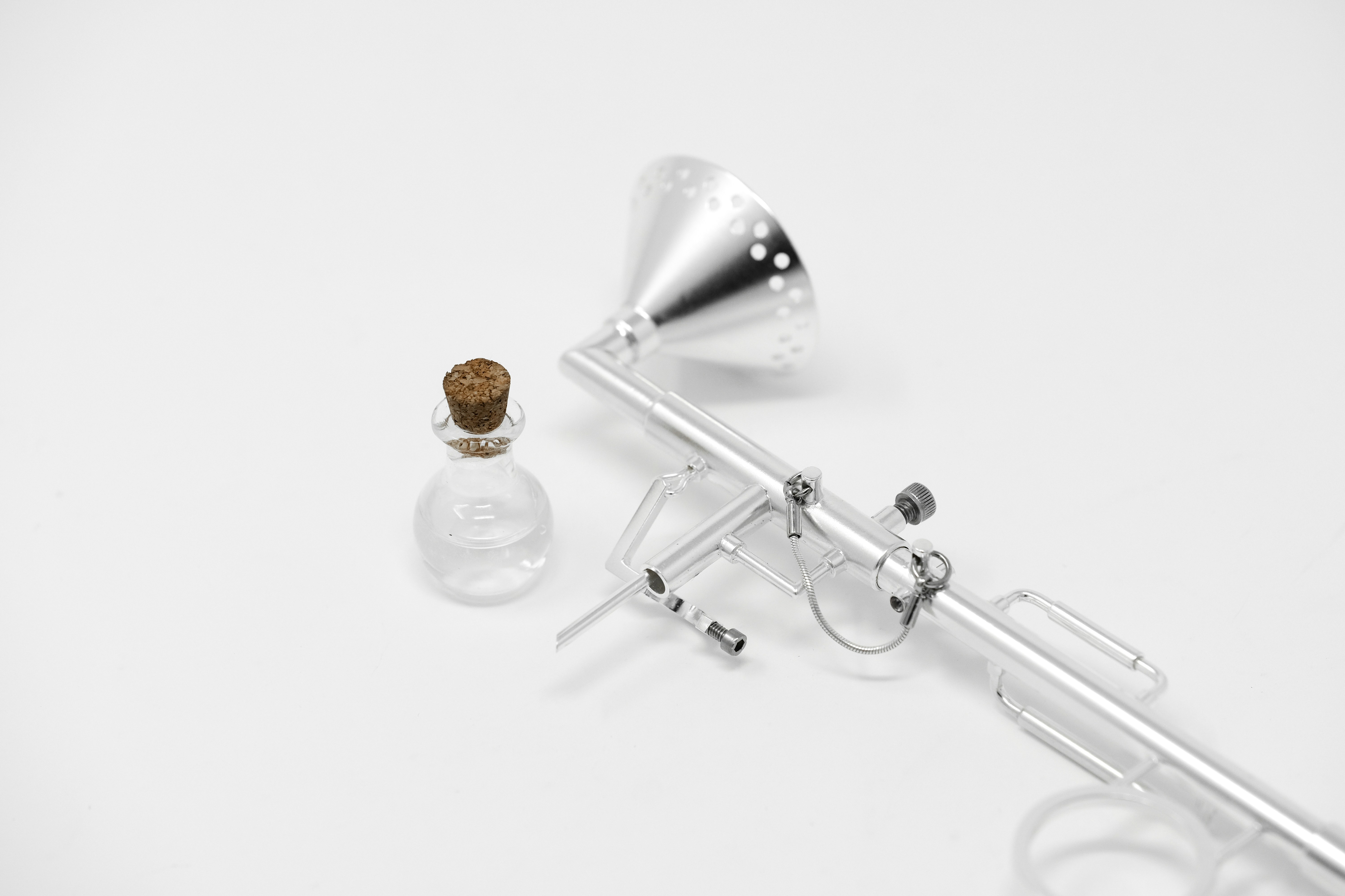 Precision in Glass: A Minimalist Brass Instrument and Tiny Bottle