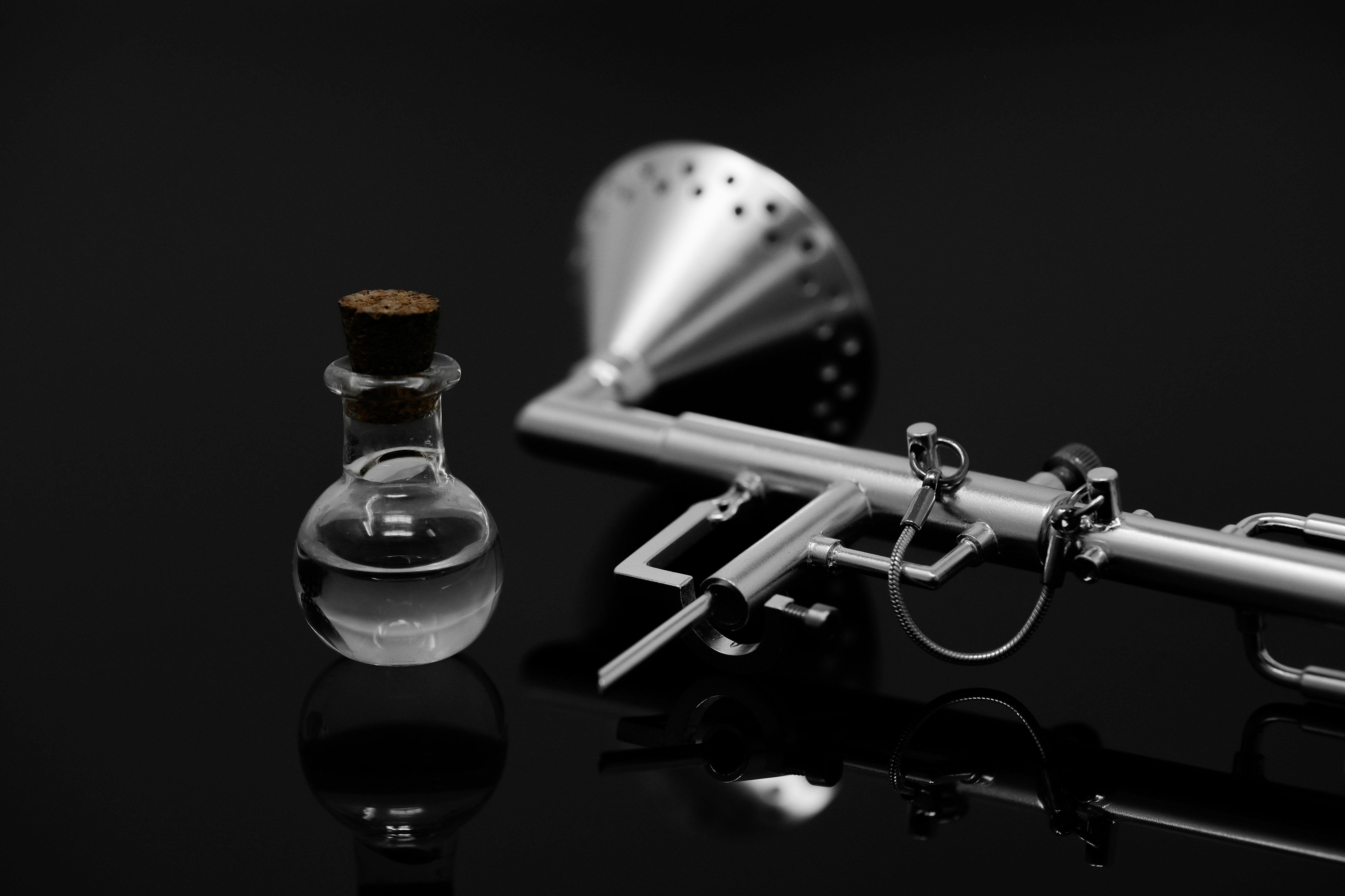 Minimalist Still Life: Glass Vessel and Studio Trombone Against Velvet Black