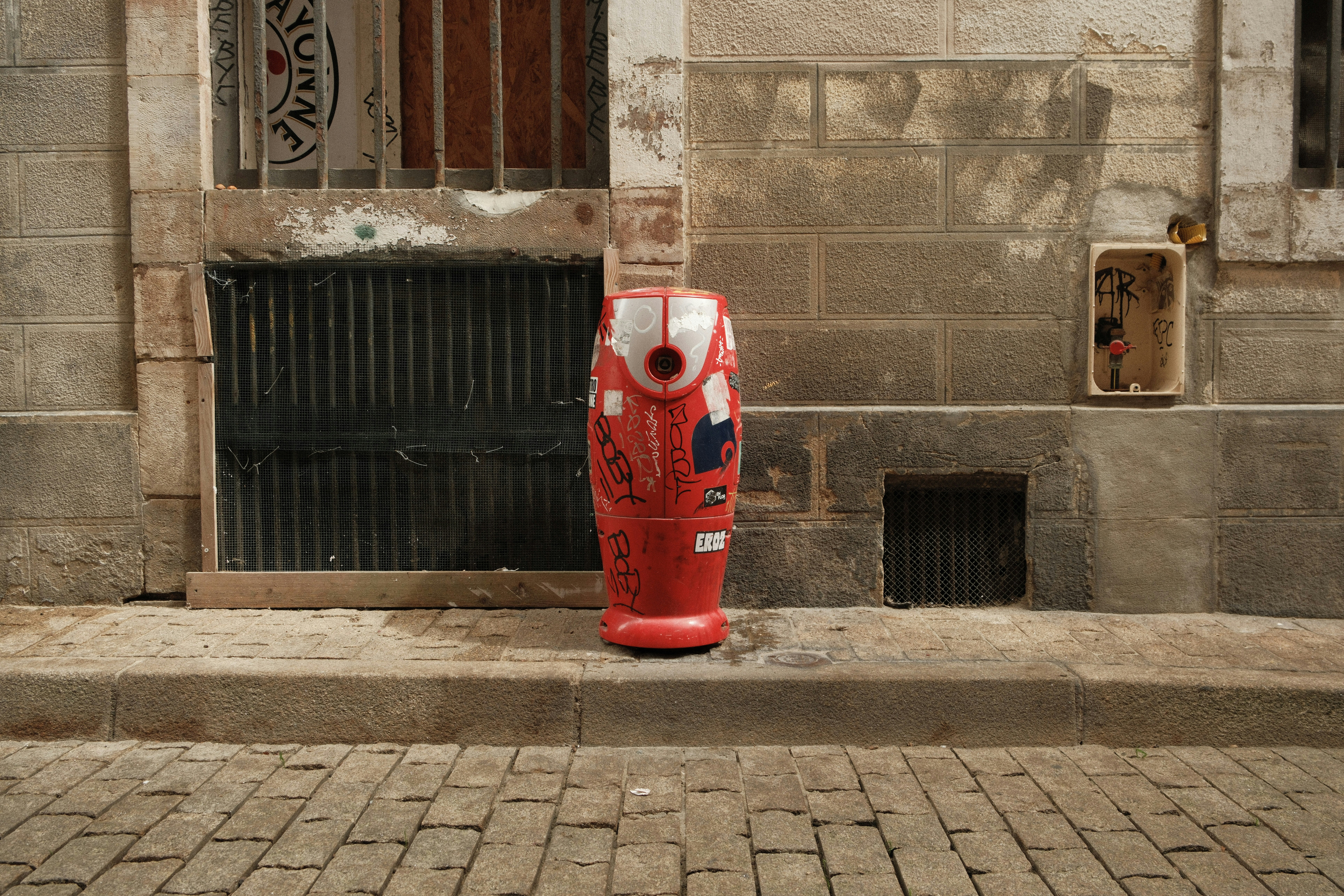 Urban Red Sentinel: A Standalone Fire Ext extinguisher Against Weathered Facade