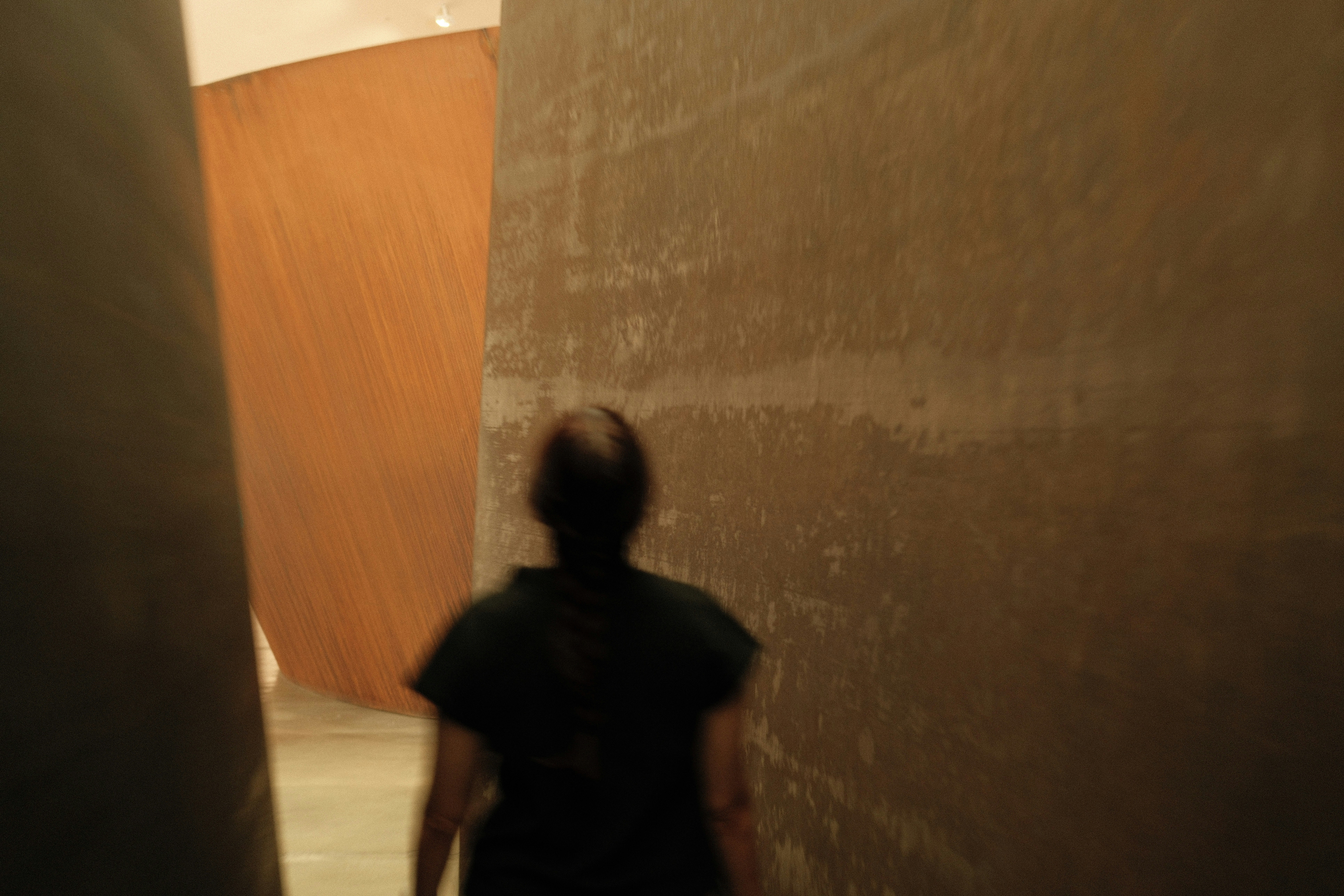 Shadowed Path: A Figure Emerges Between Concrete Walls