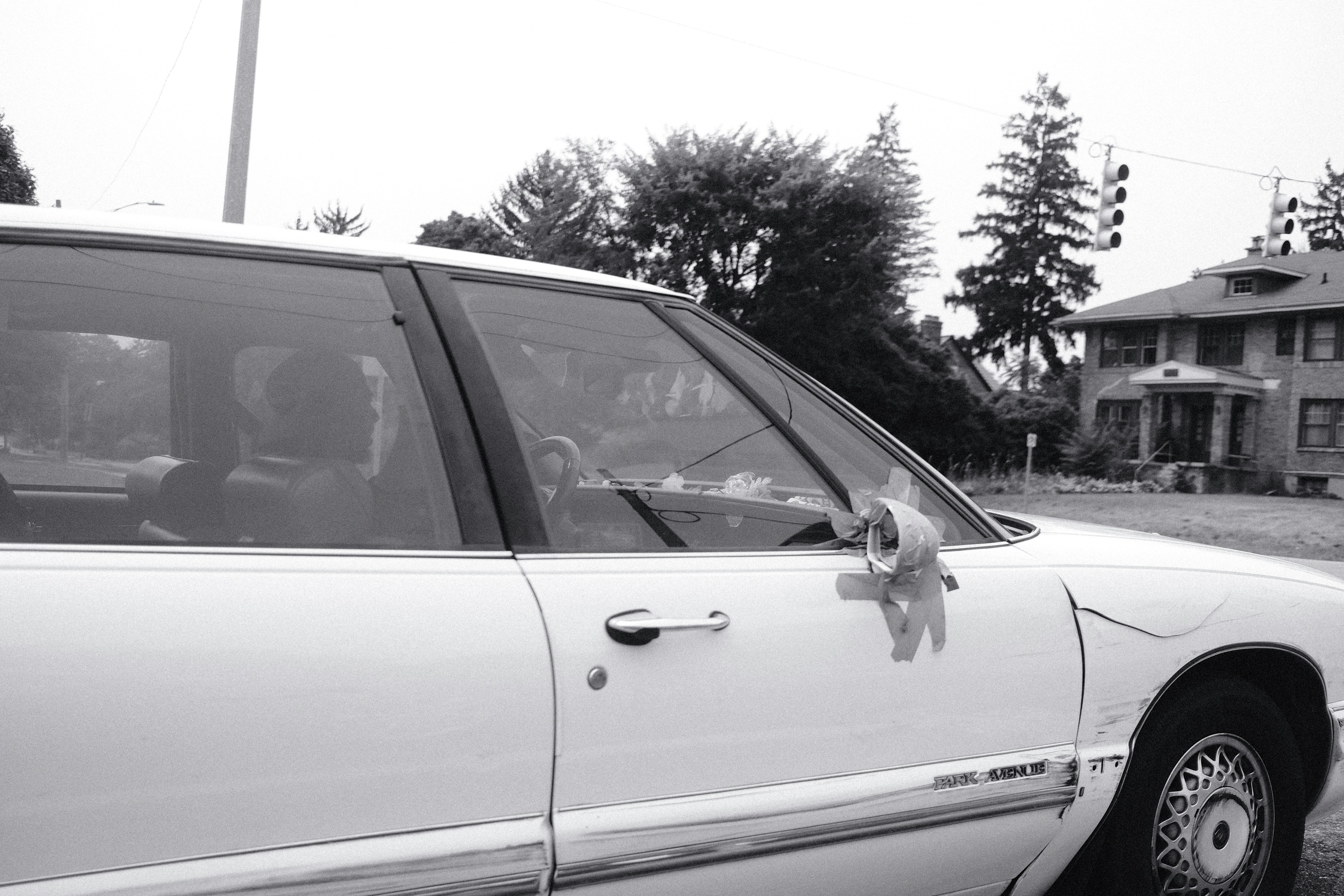 Mid‑sixties sedan with a bow: a candid street moment in monochrome