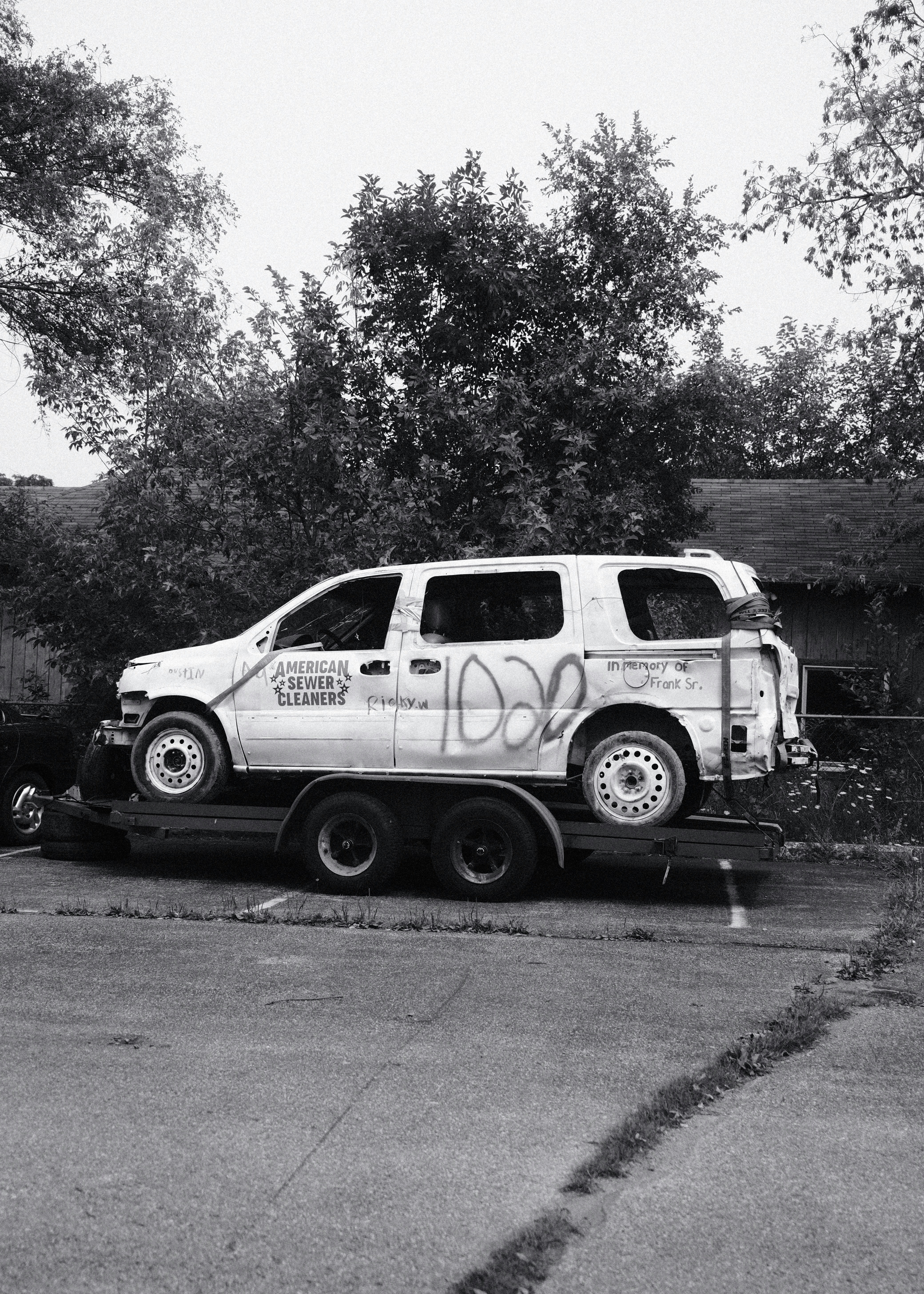 Graffiti-etched van on a rusted trailer in a quiet lot