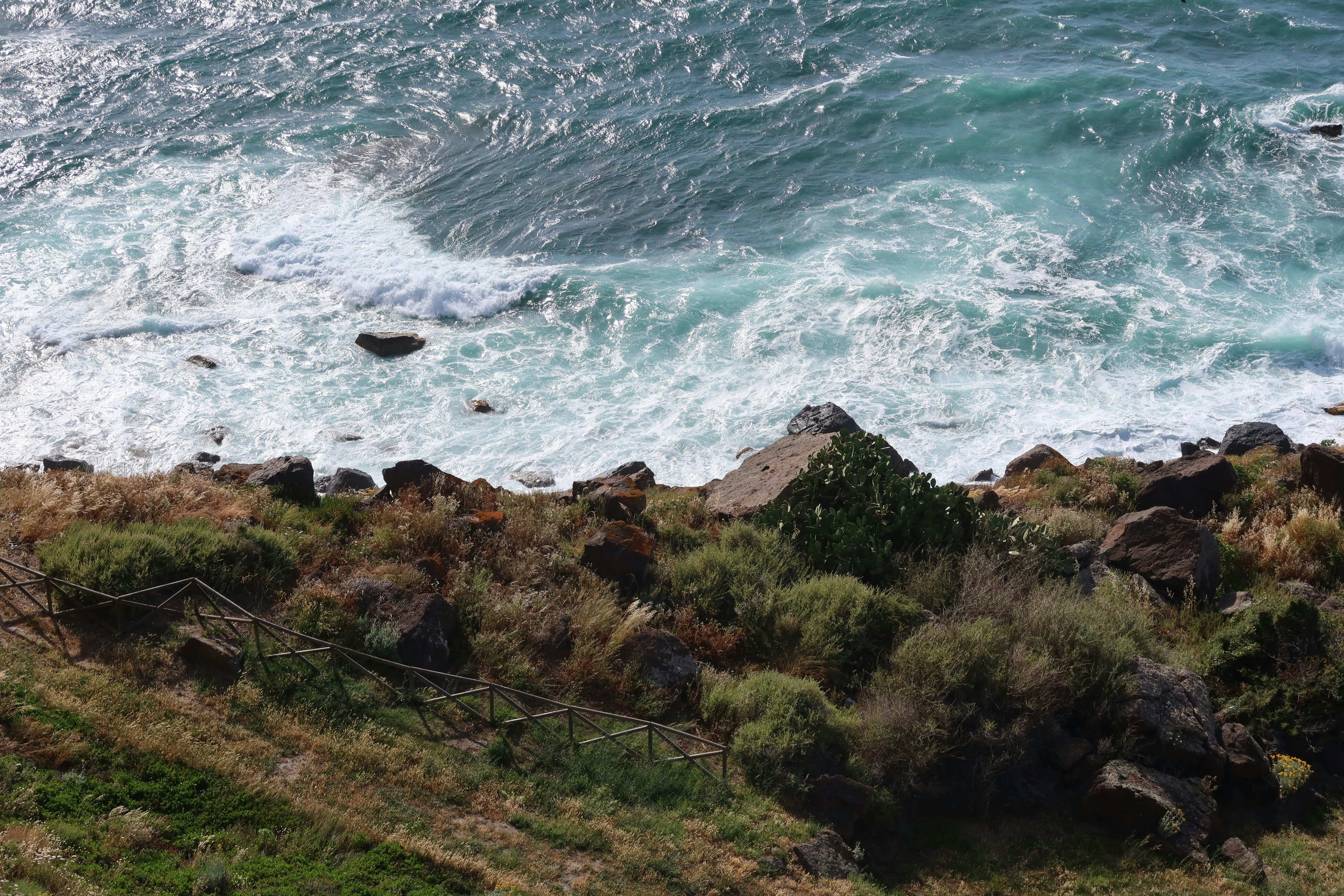 Cliffside Shoreline: Tide, Rocks, and Weathered Steps
