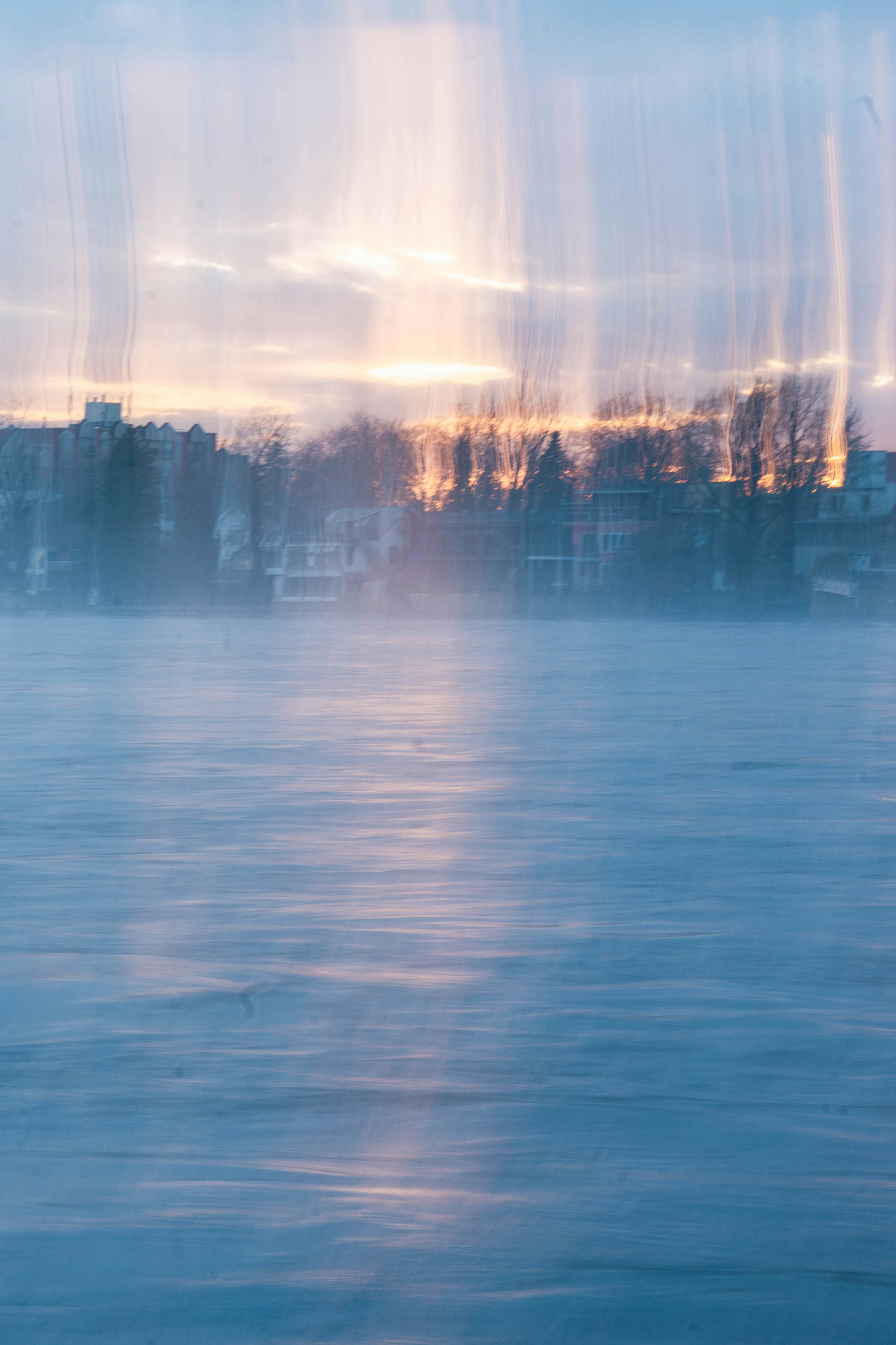 River Veil: Sunset Reflections through Moving Glass