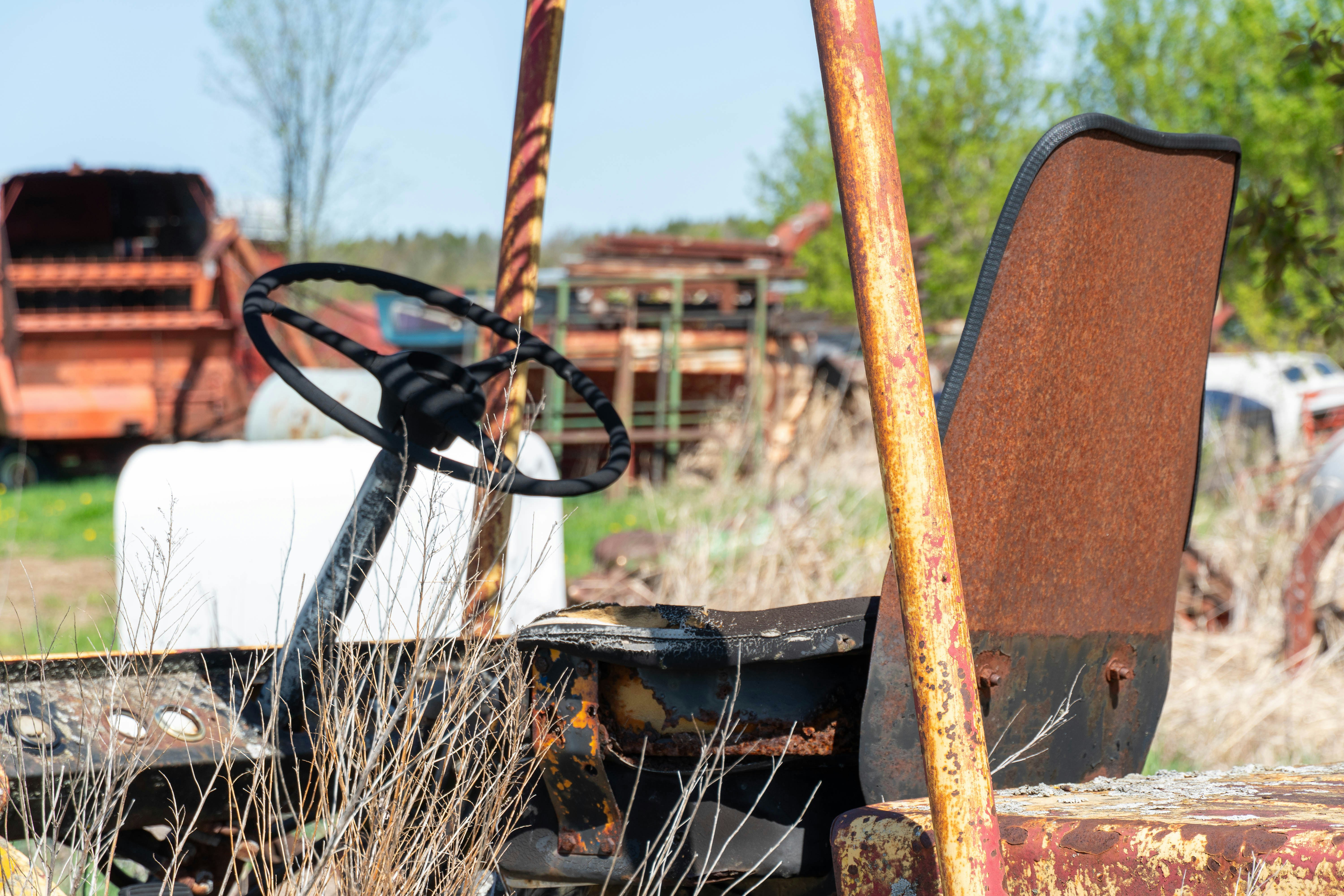 Rust and Remnants: A Sidelined Steering Wheel in a Field of Decay