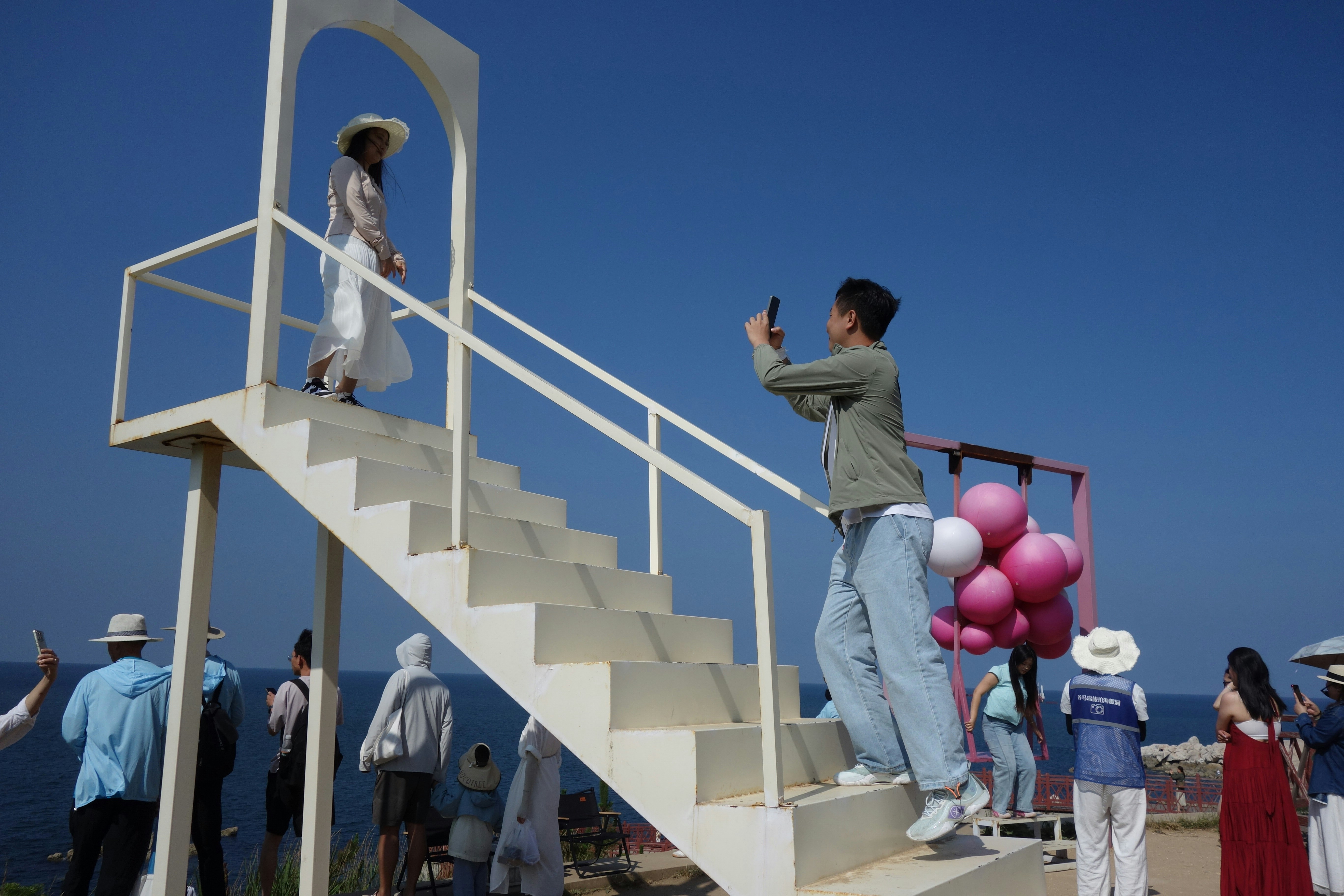 Staircase to a Moment: A Photographer Captures a Woman in White Above the Beach Scene