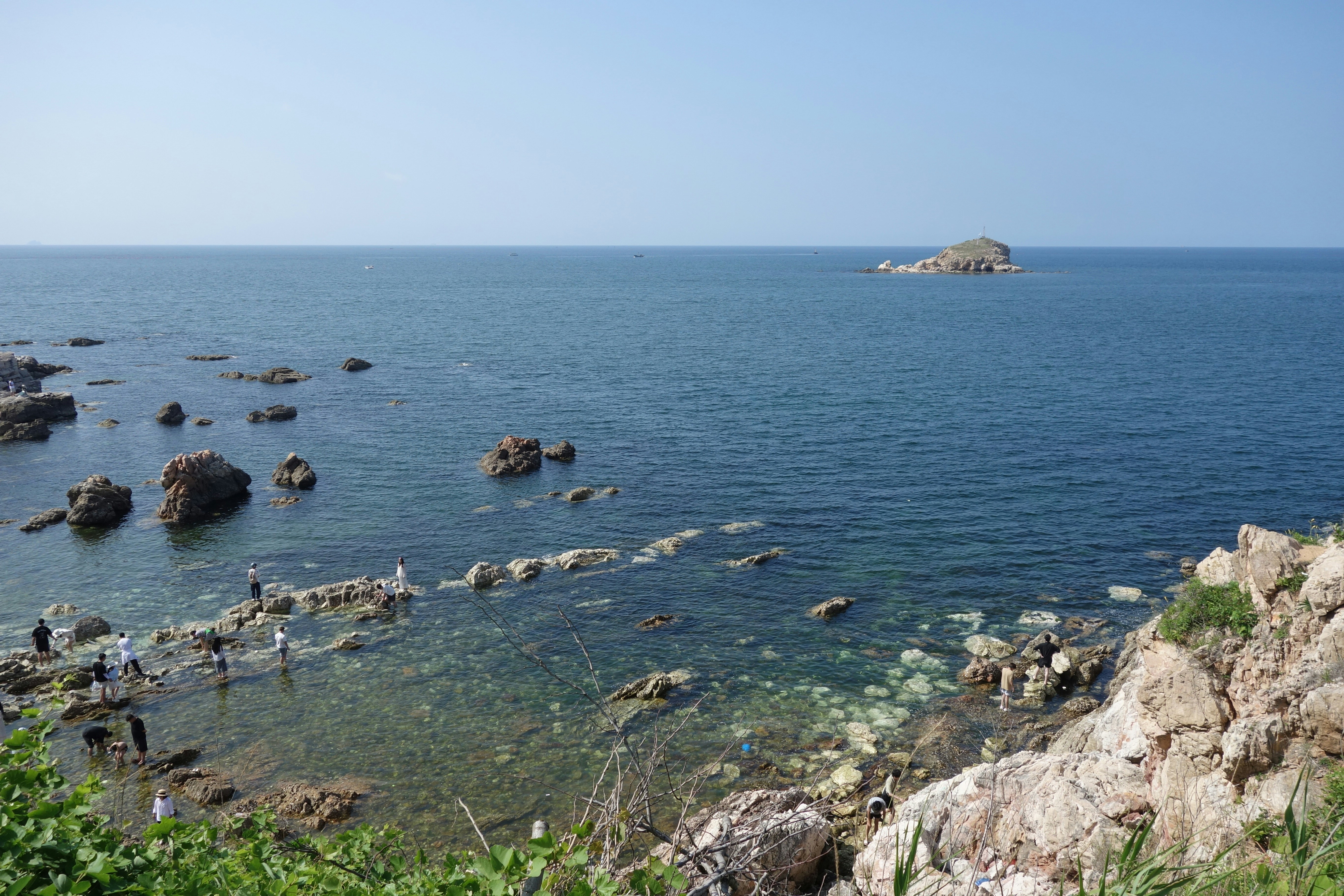 Coastal Mosaic: Rock Pools, People, and a Distant Island