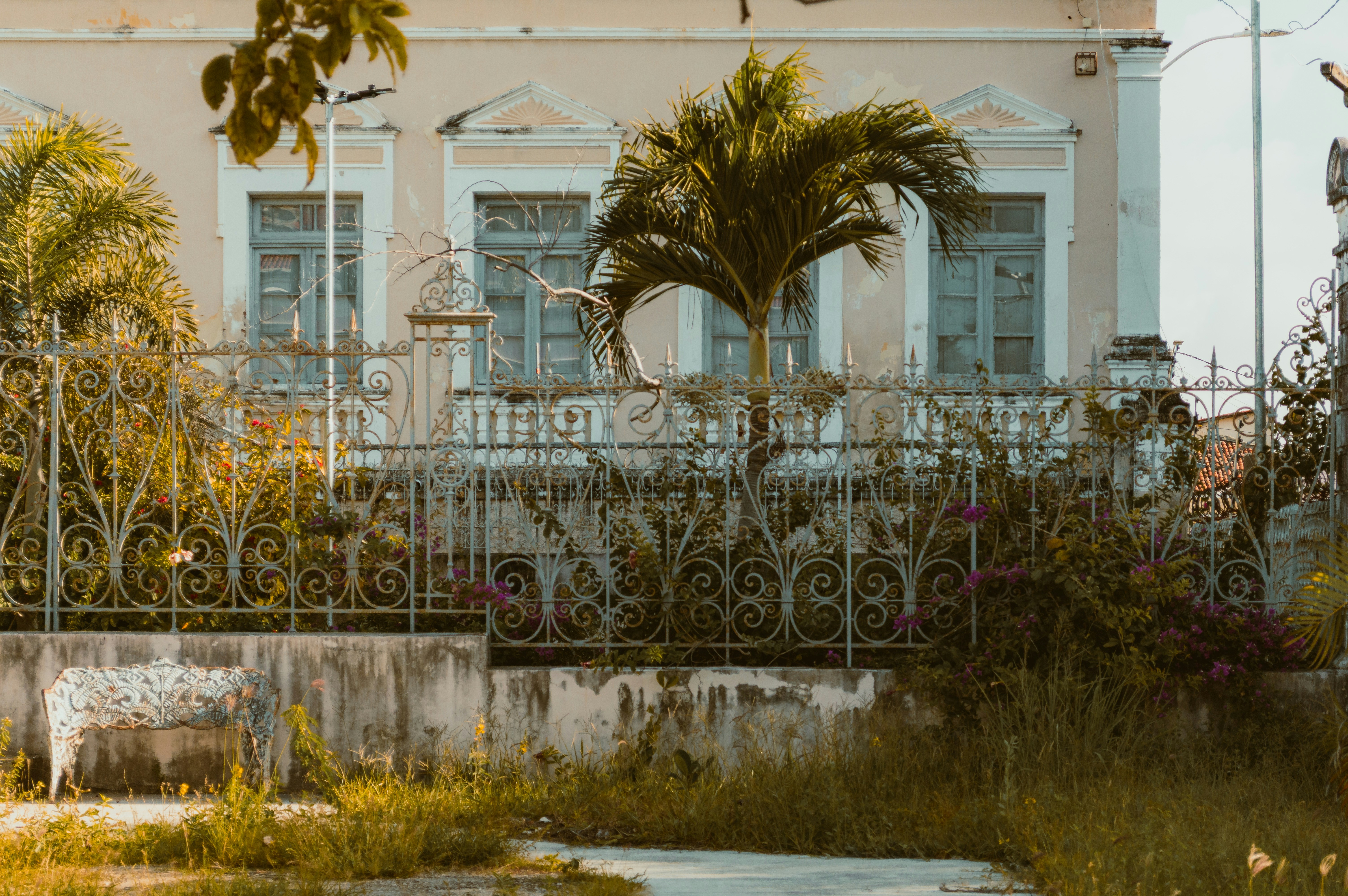 Pastel mansion behind an iron fence in tropical afternoon light