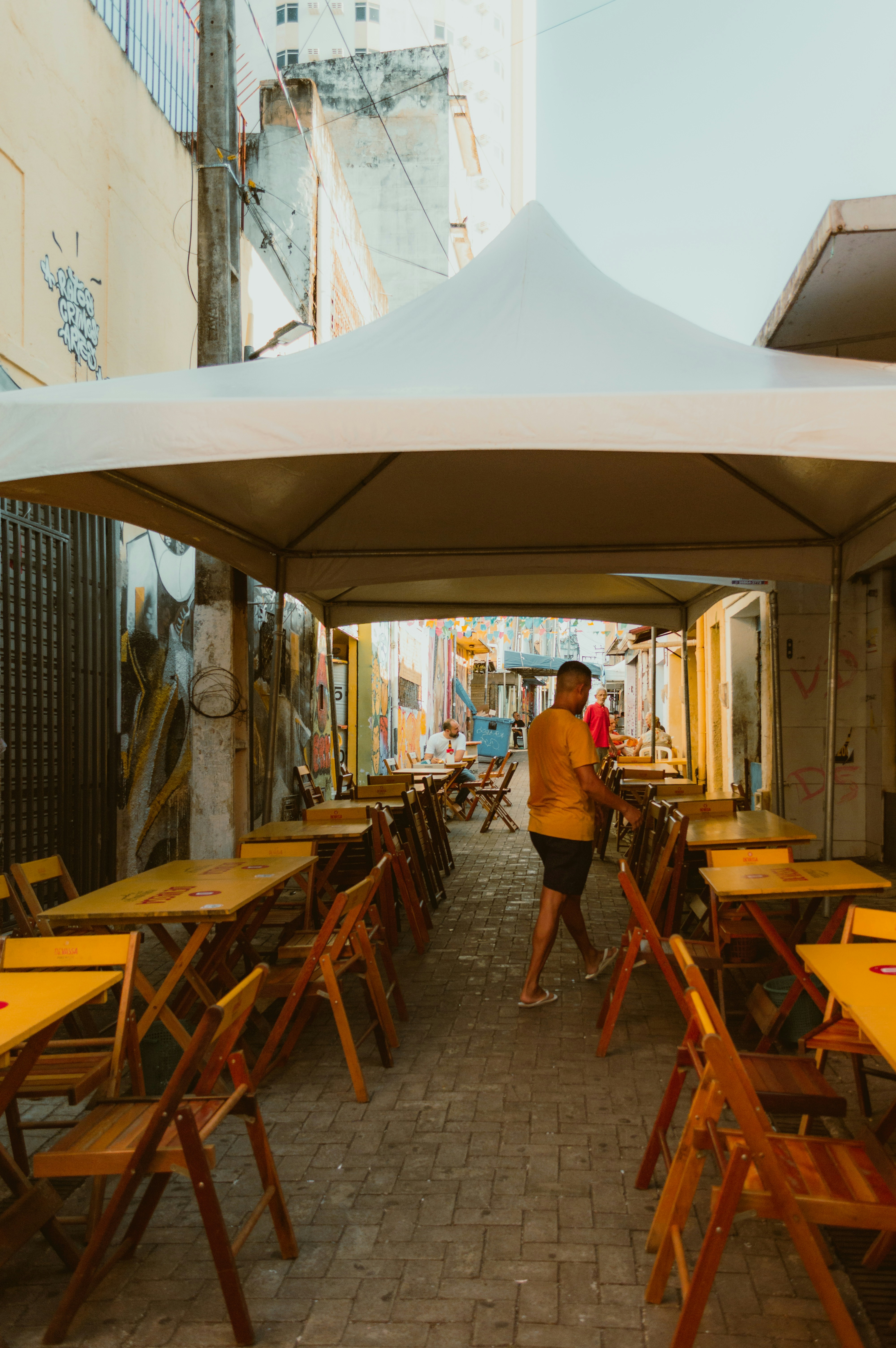 Street Terrace under White Canopy: A Quiet Moment in Colorful Alley