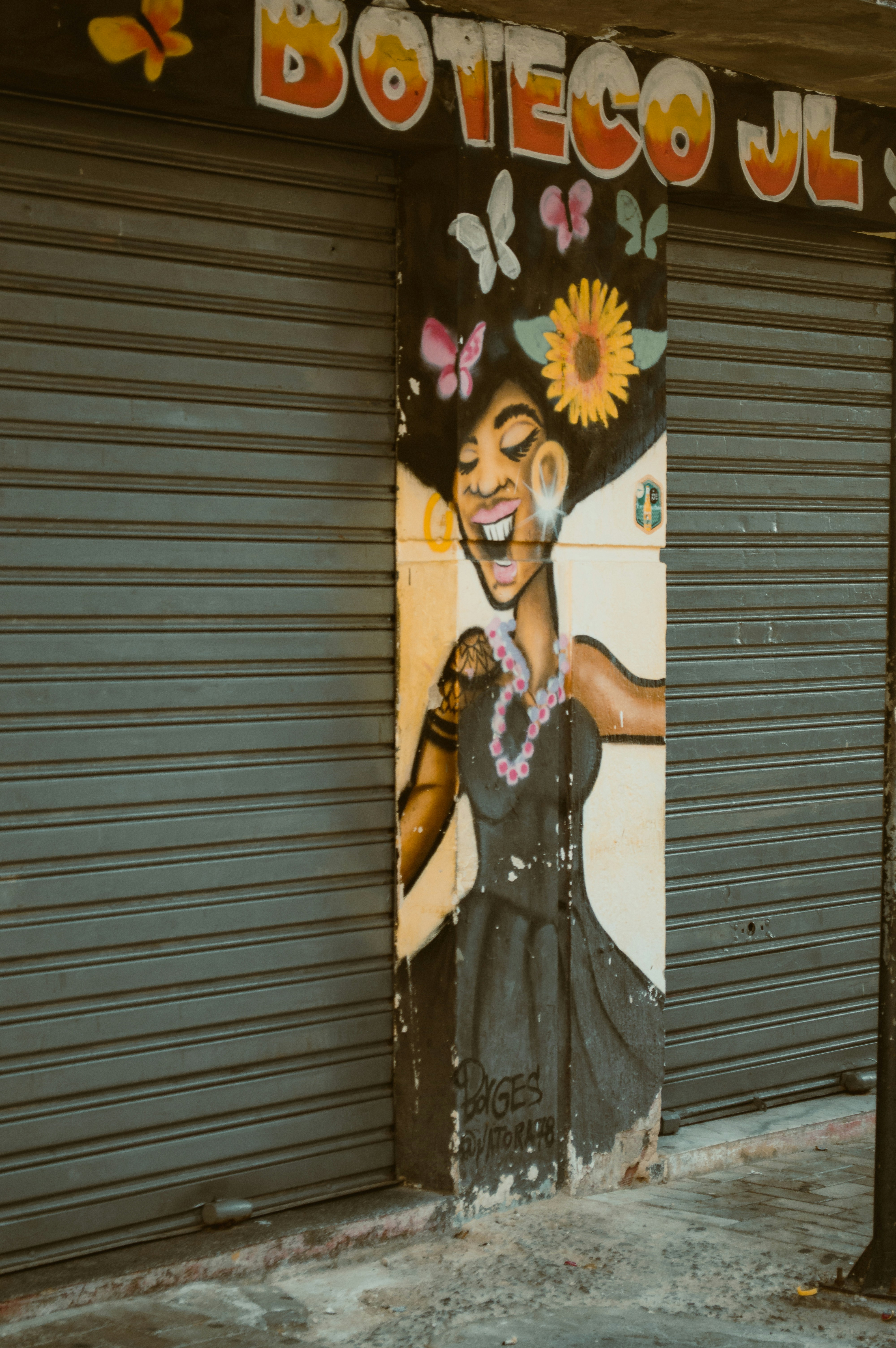 Joyful mural in a sunlit alley: a smiling figure with a flower crown