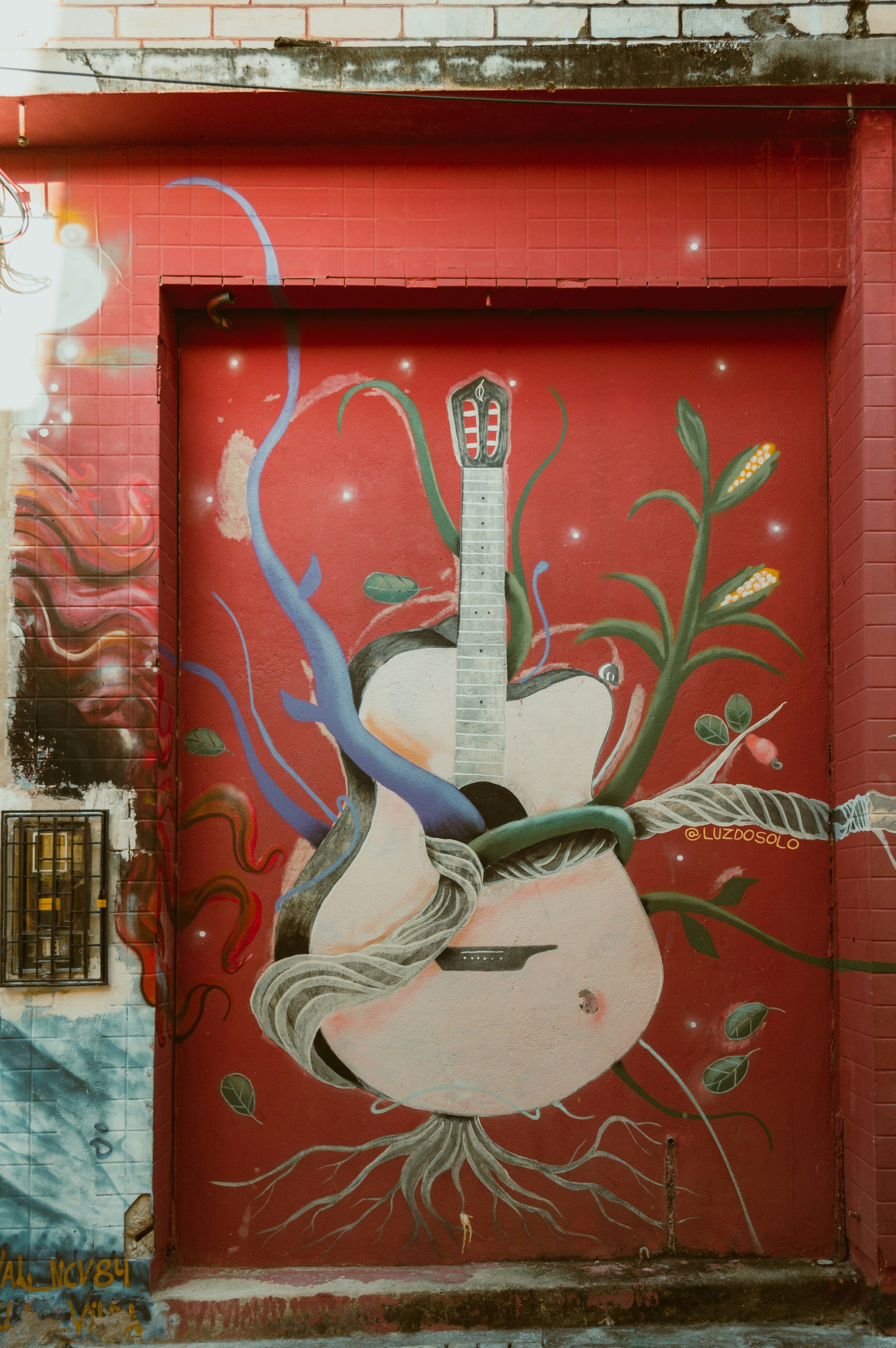 Guitar Rooted in a Red Wall: Surreal Street Mural