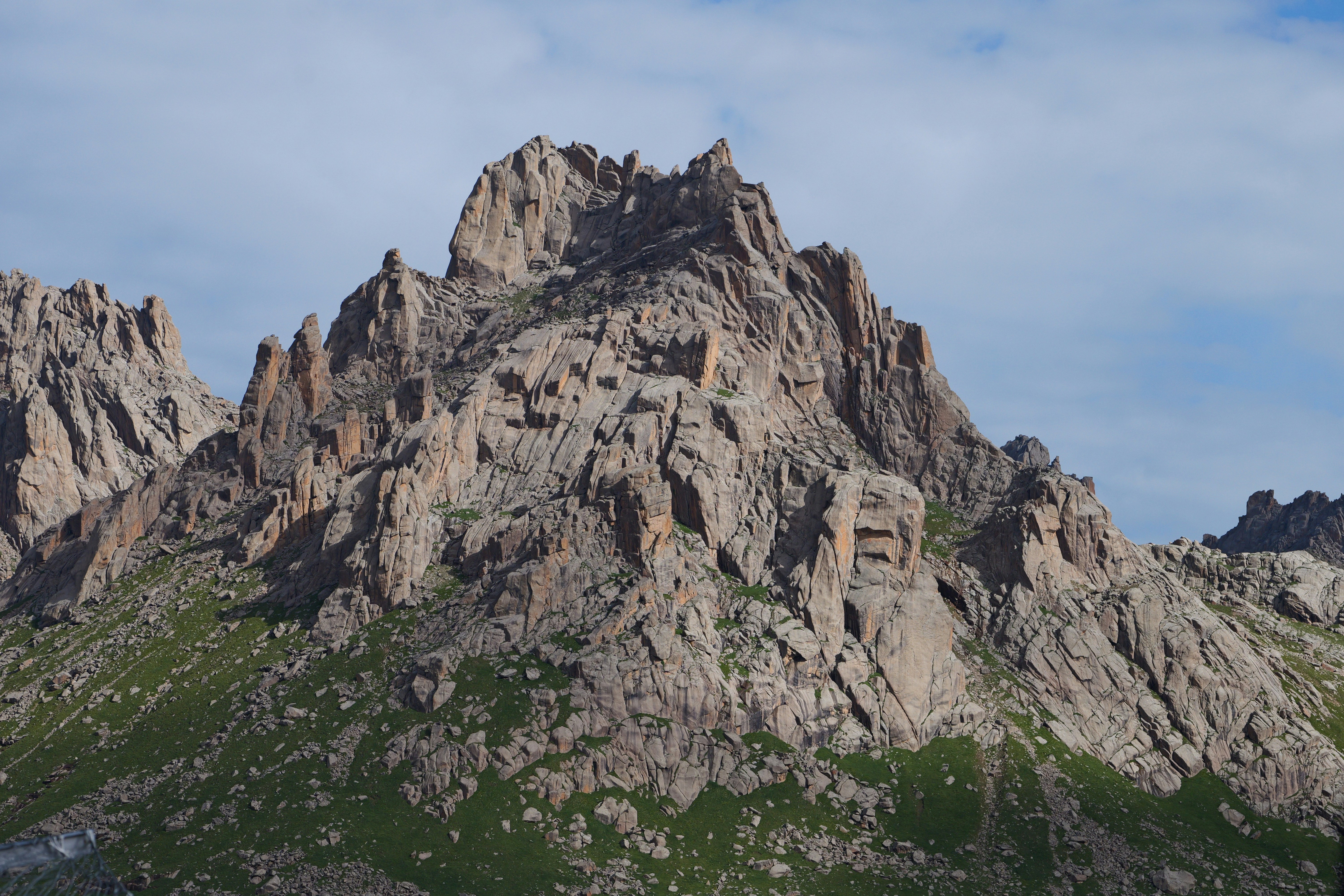 Rugged Summit: Jagged Peaks Rising Above Verdant Foot