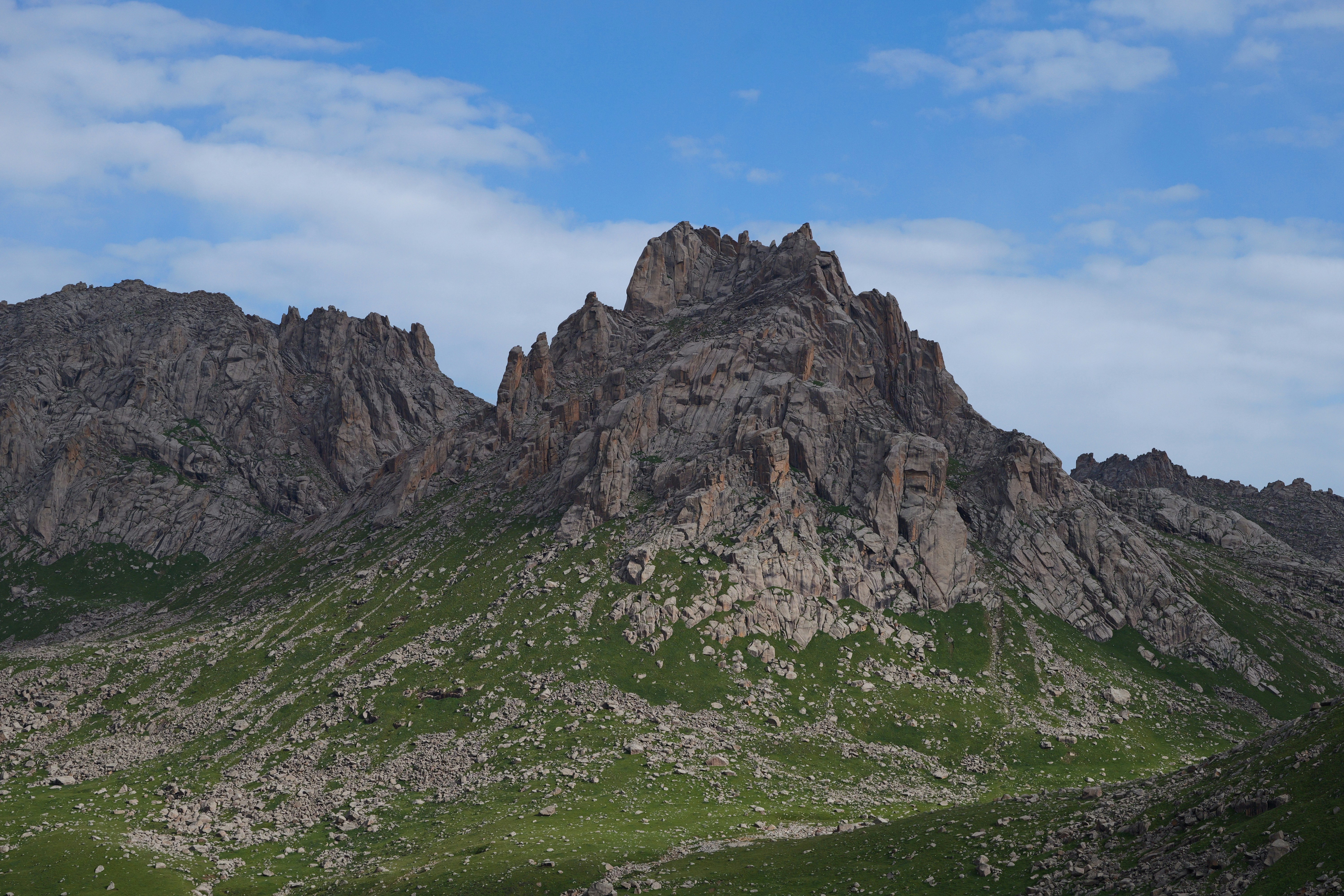 Rugged Summit Rising Over Green Slopes