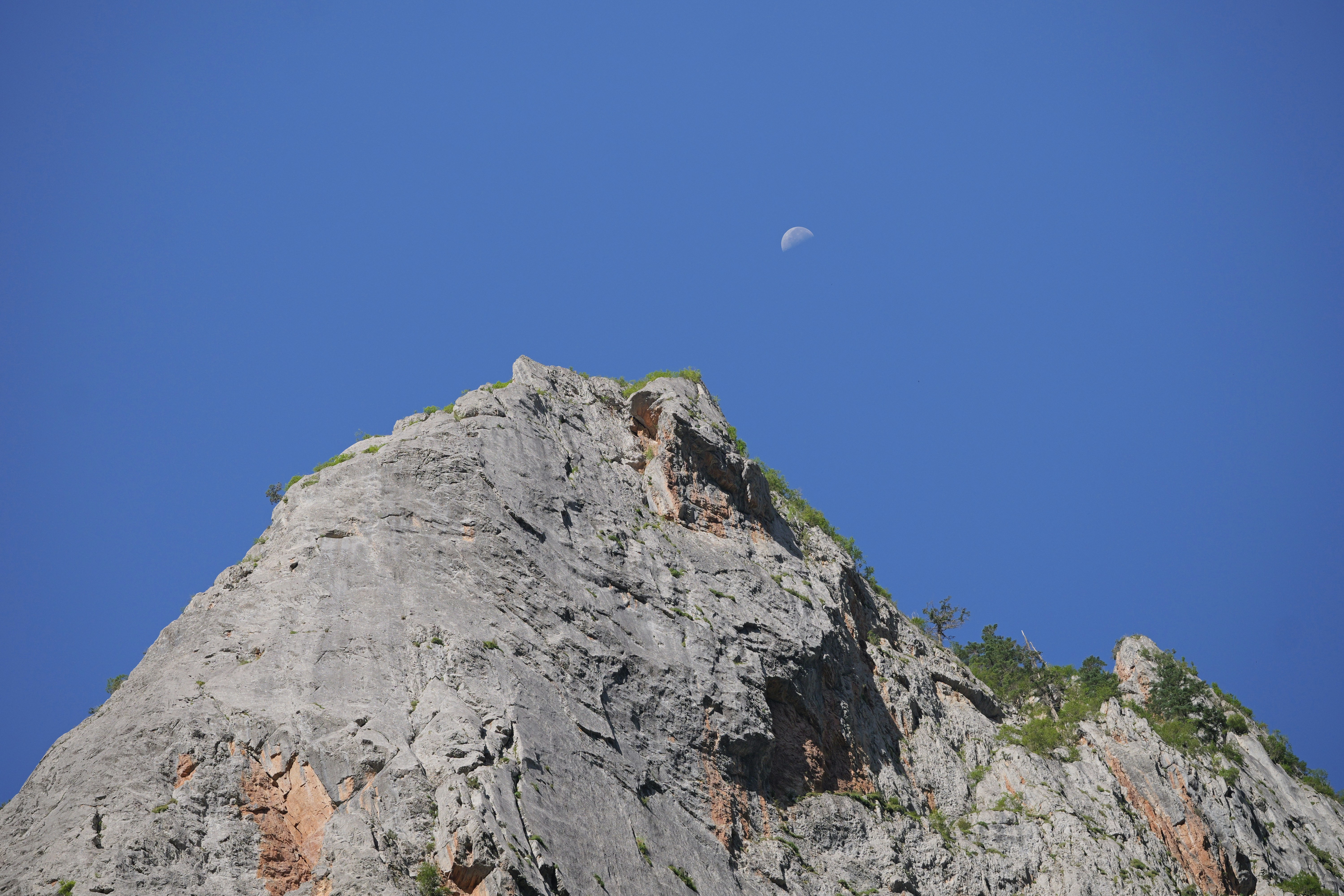 Moon over rugged summit: a quiet sky above weathered rock