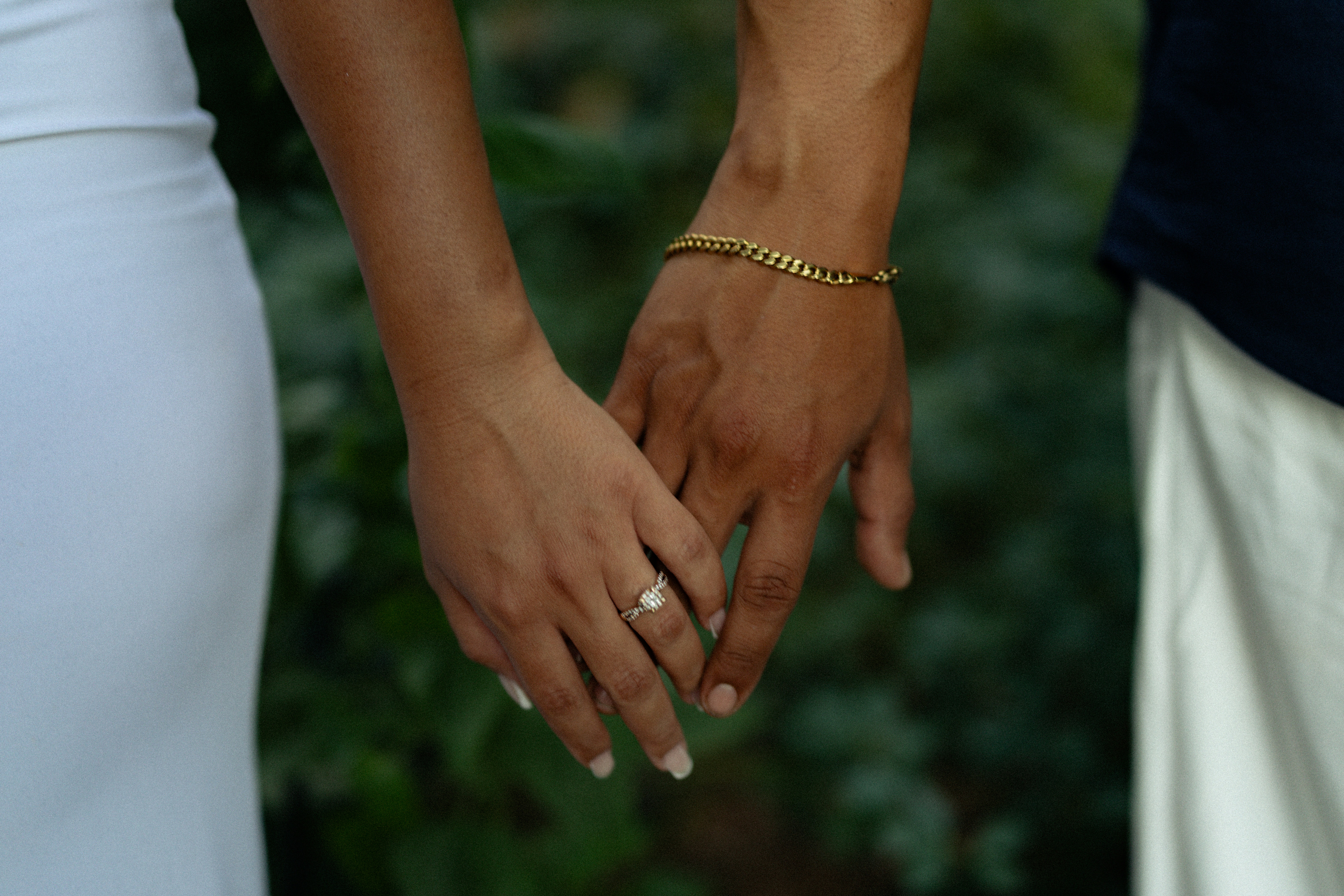 Elegant union: clasped hands with diamond ring in a green backdrop