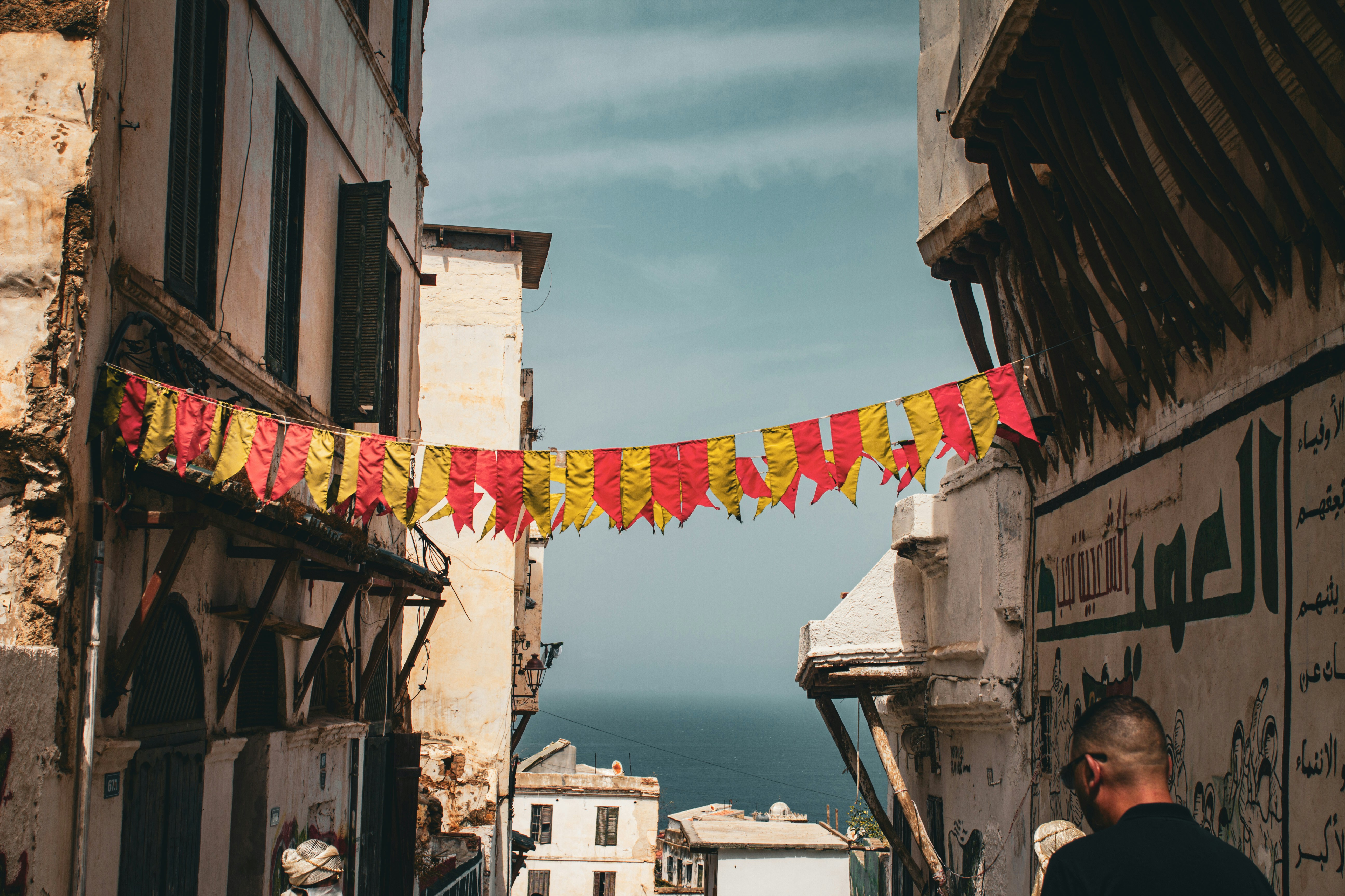 Sunlit Alleyway with Colorful Banners Overlooking the Sea
