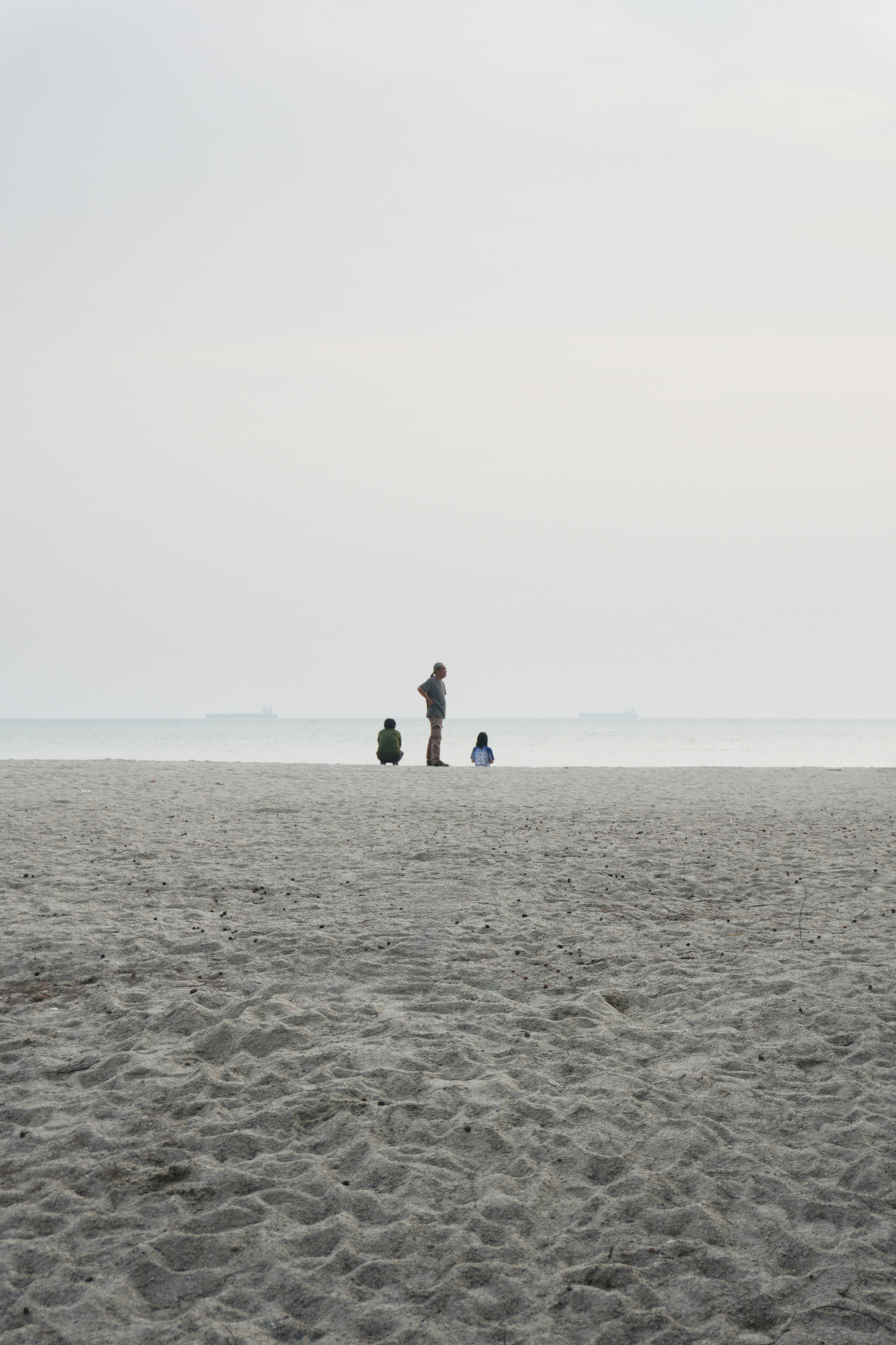 A Quiet Beach Assembly: Three Figures in Soft Horizon Light