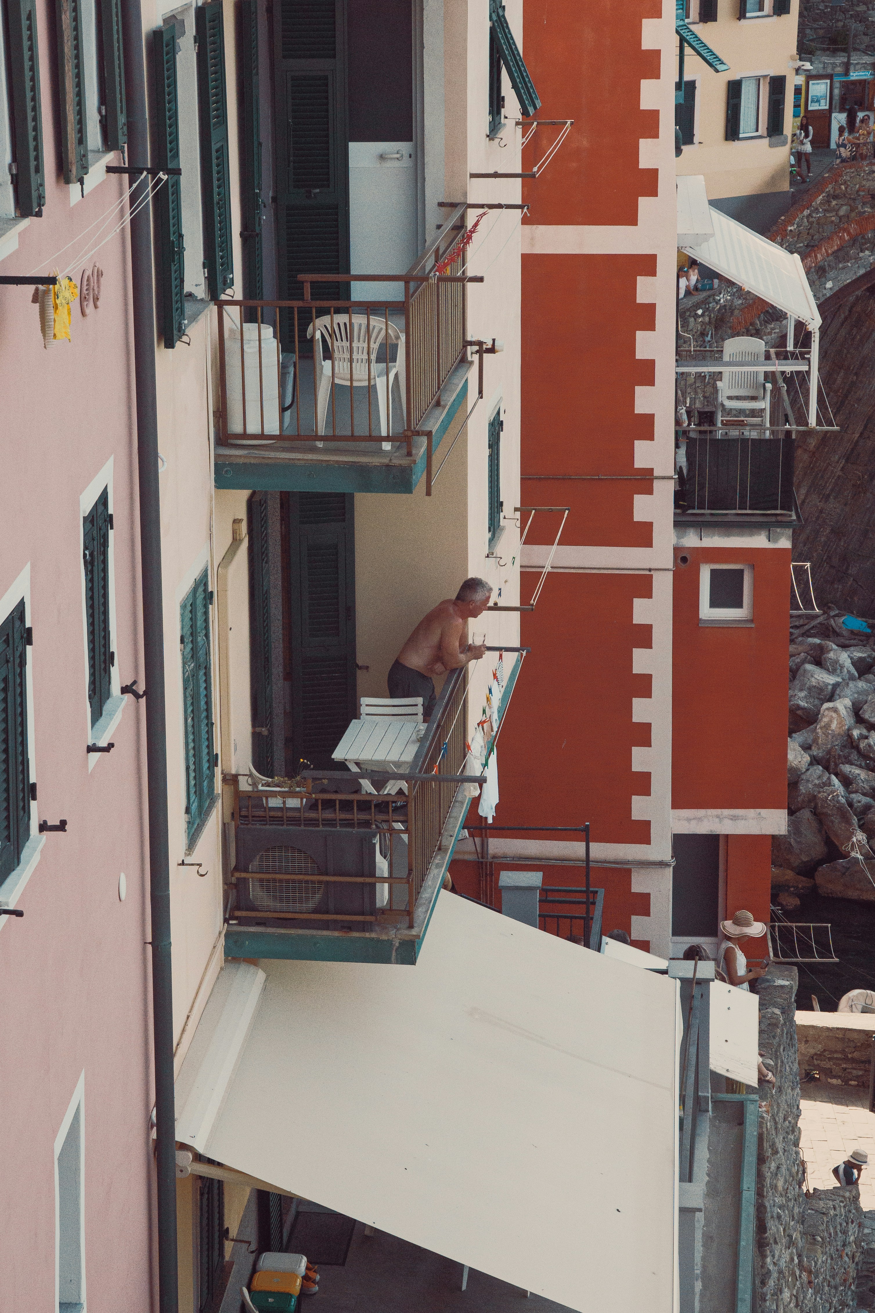 Balcony Observer: A Shirtless Figure Surfaces Over the Citadel of Color
