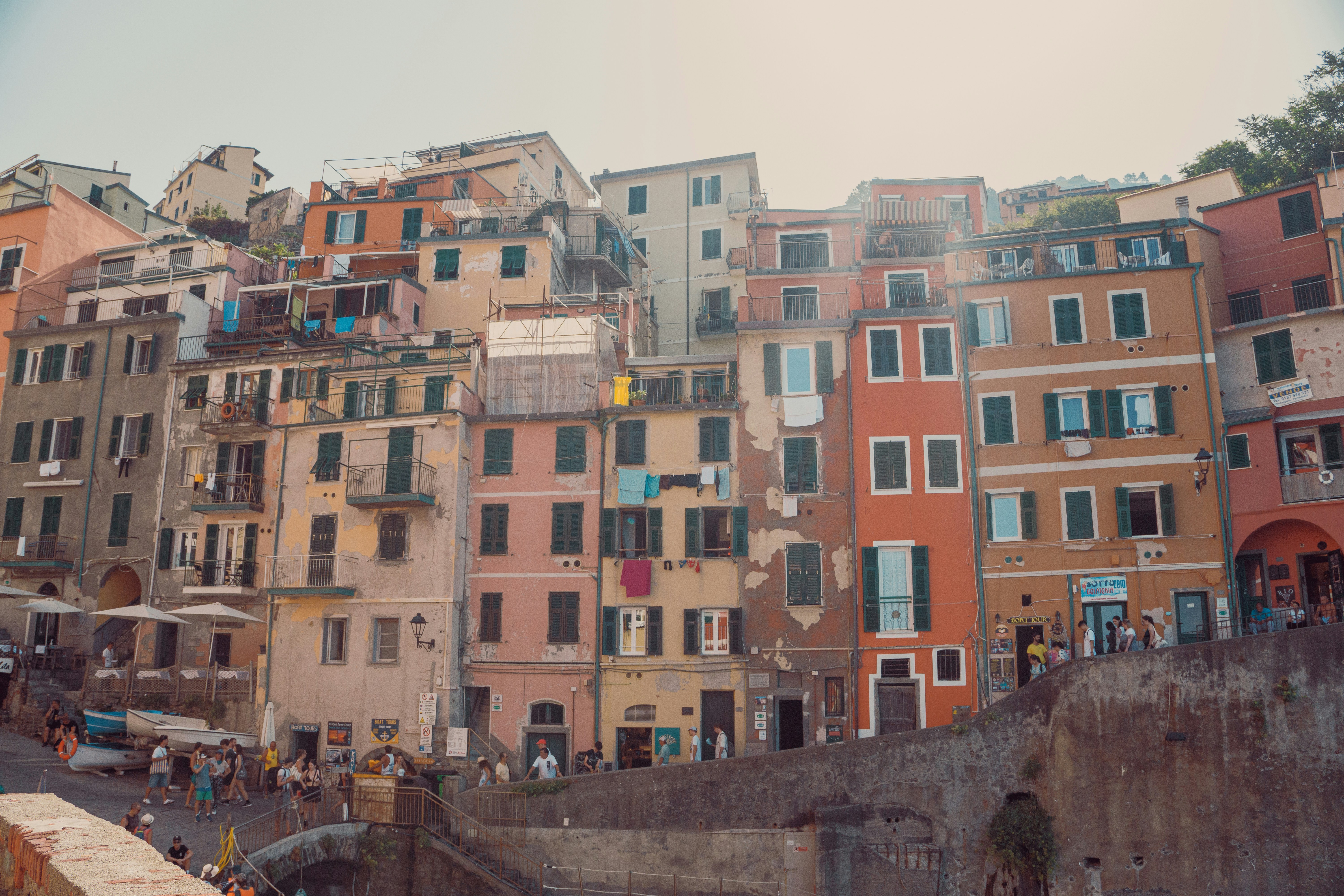 Colorful cliffside houses of a Ligurian harbor cascade into a sunlit plaza