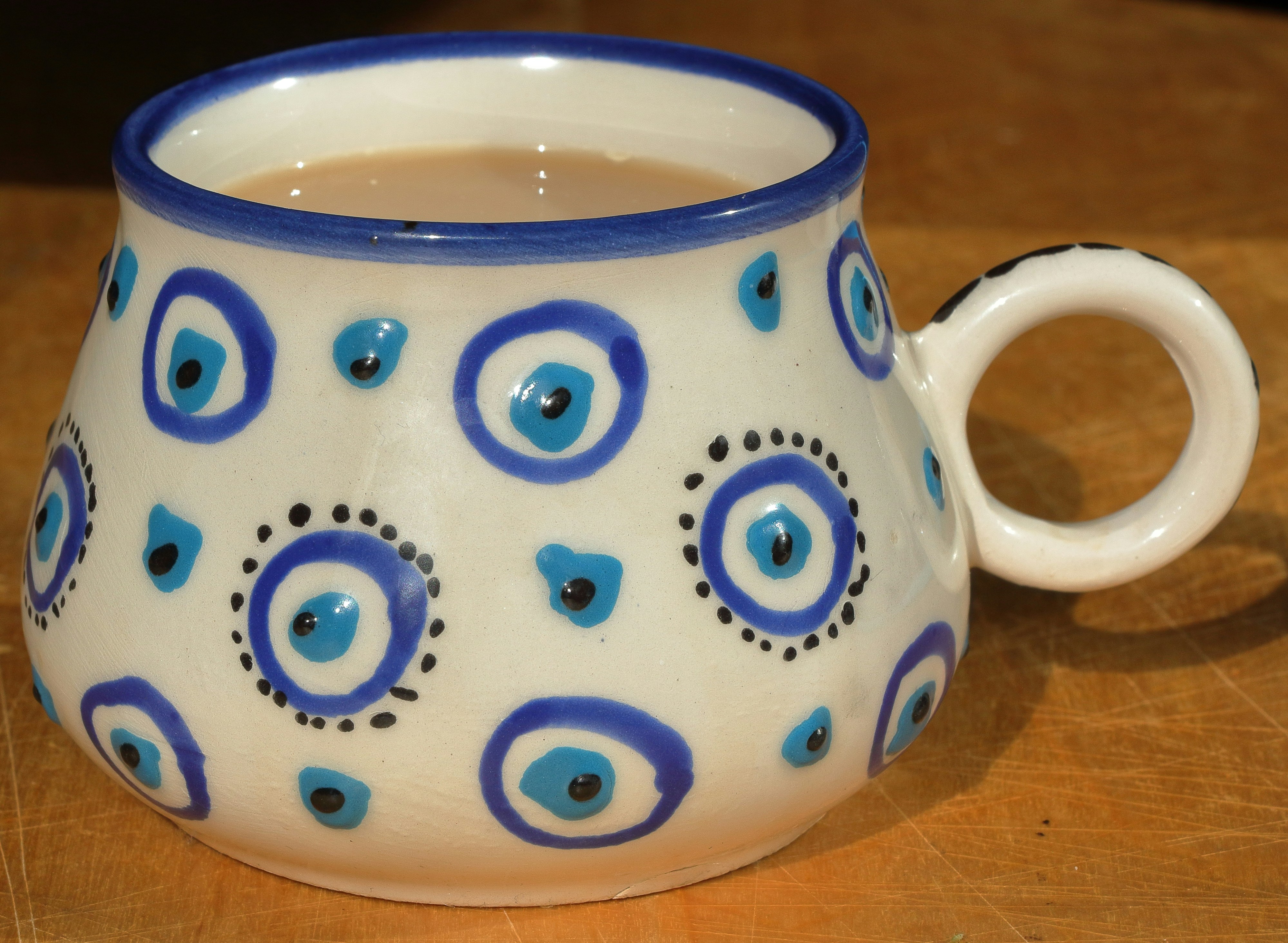 Ceramic Mug with Concentric Eye Pattern on a Wooden Table
