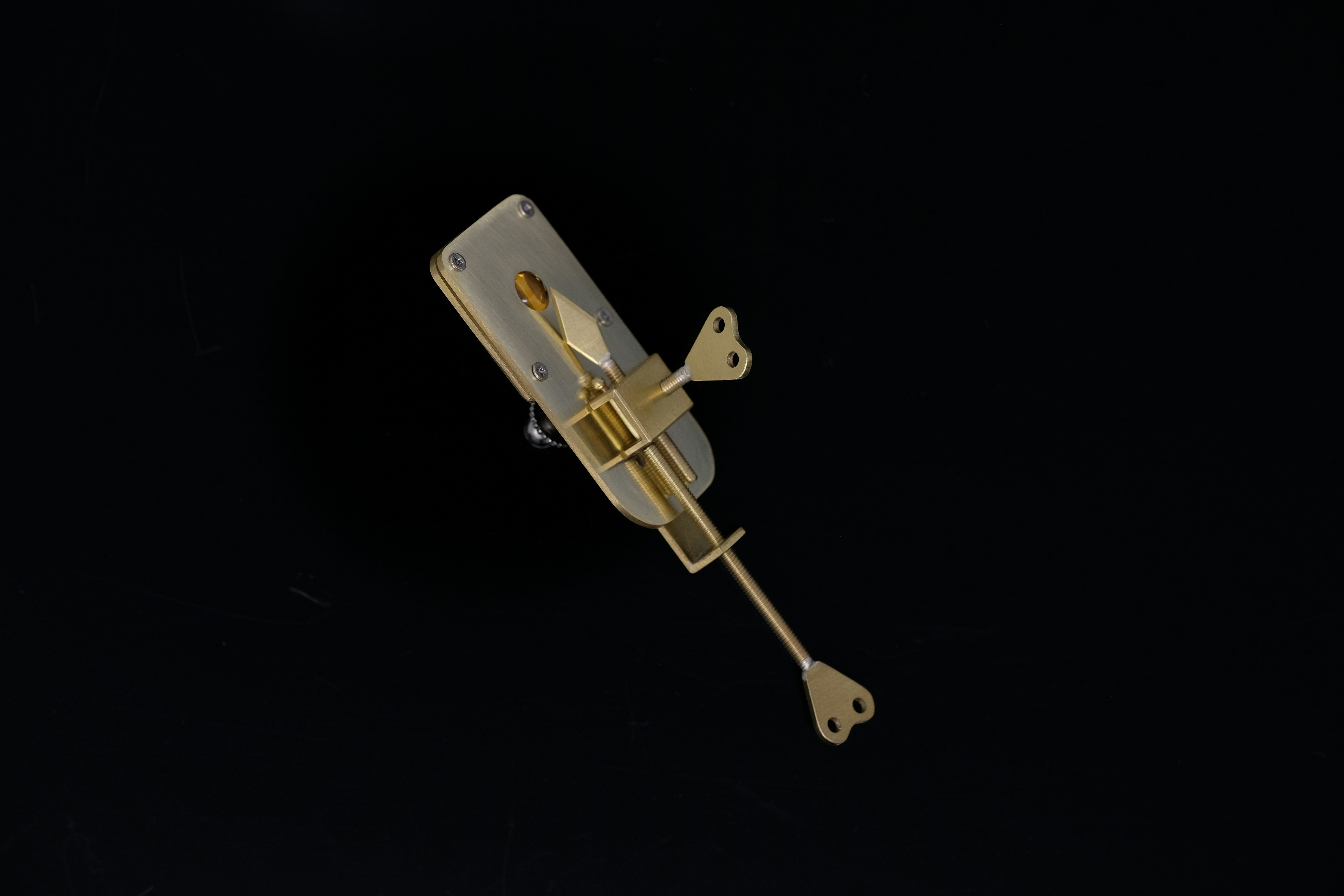 Gold-toned mechanical latch suspended in a black void