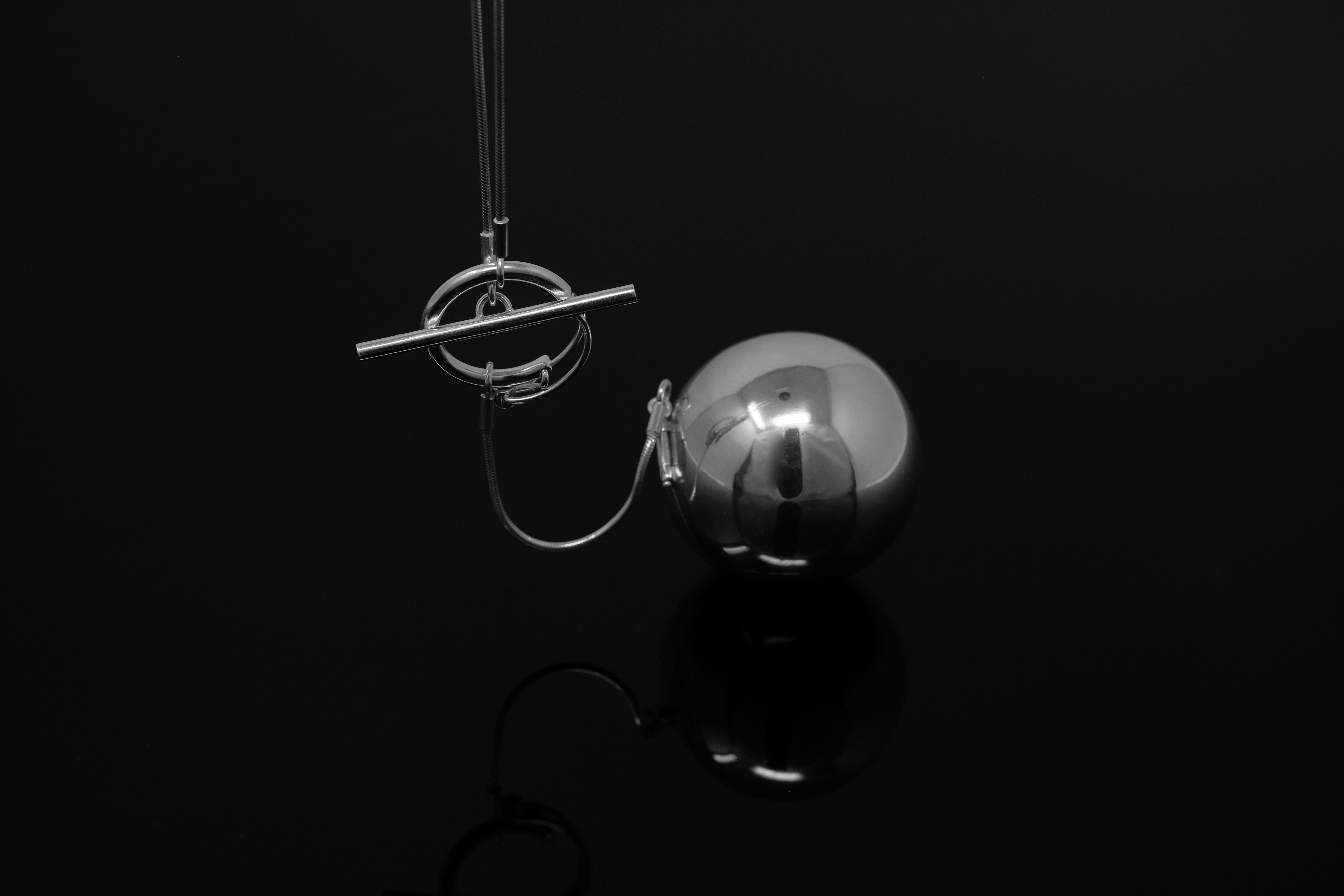 Suspended Geometry: A Glossy Sphere and Wire Sculpture in Noir