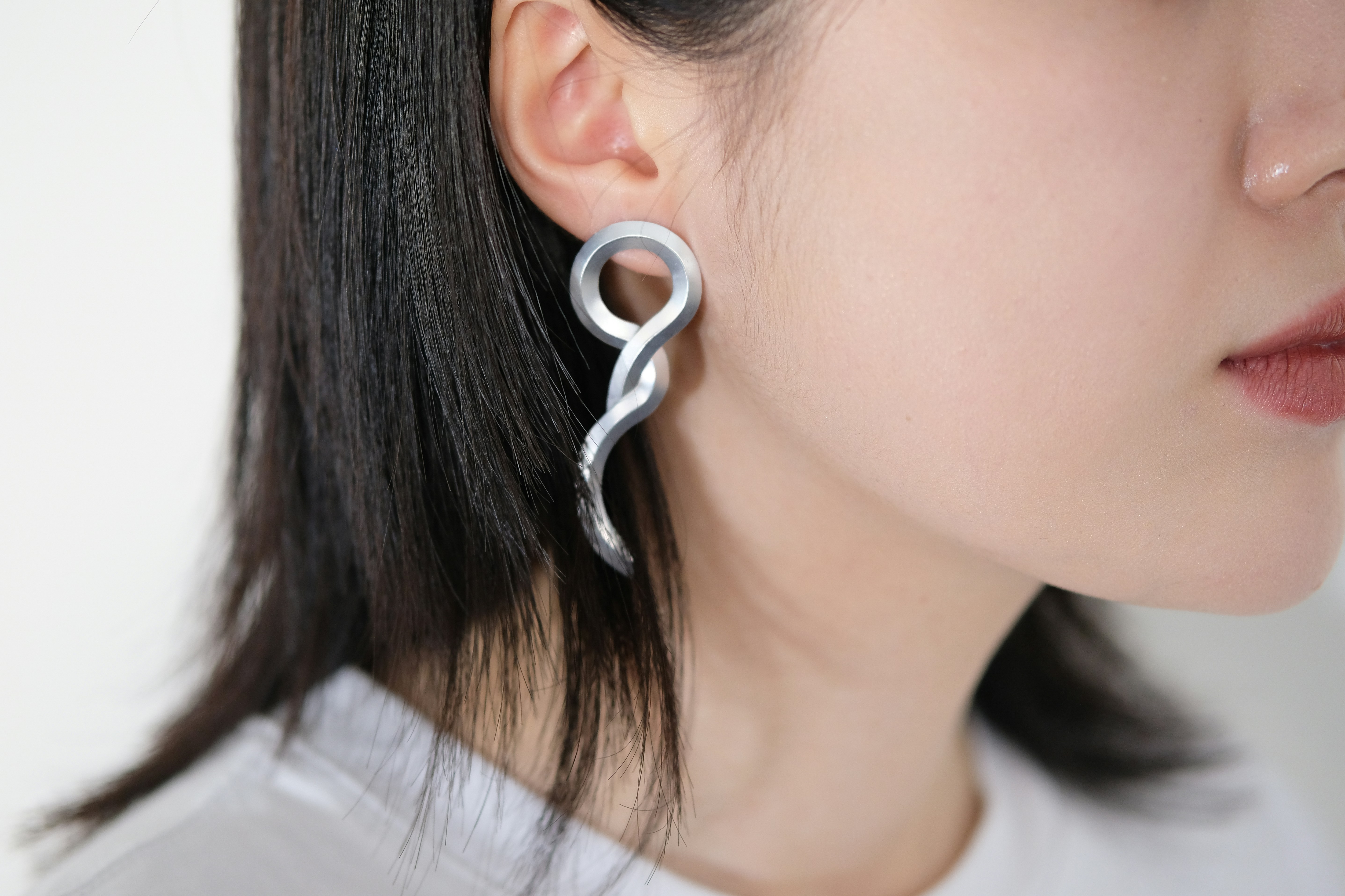Minimalist Curve: The Earring’s Silvery Loop Emerges from Soft Portraiture