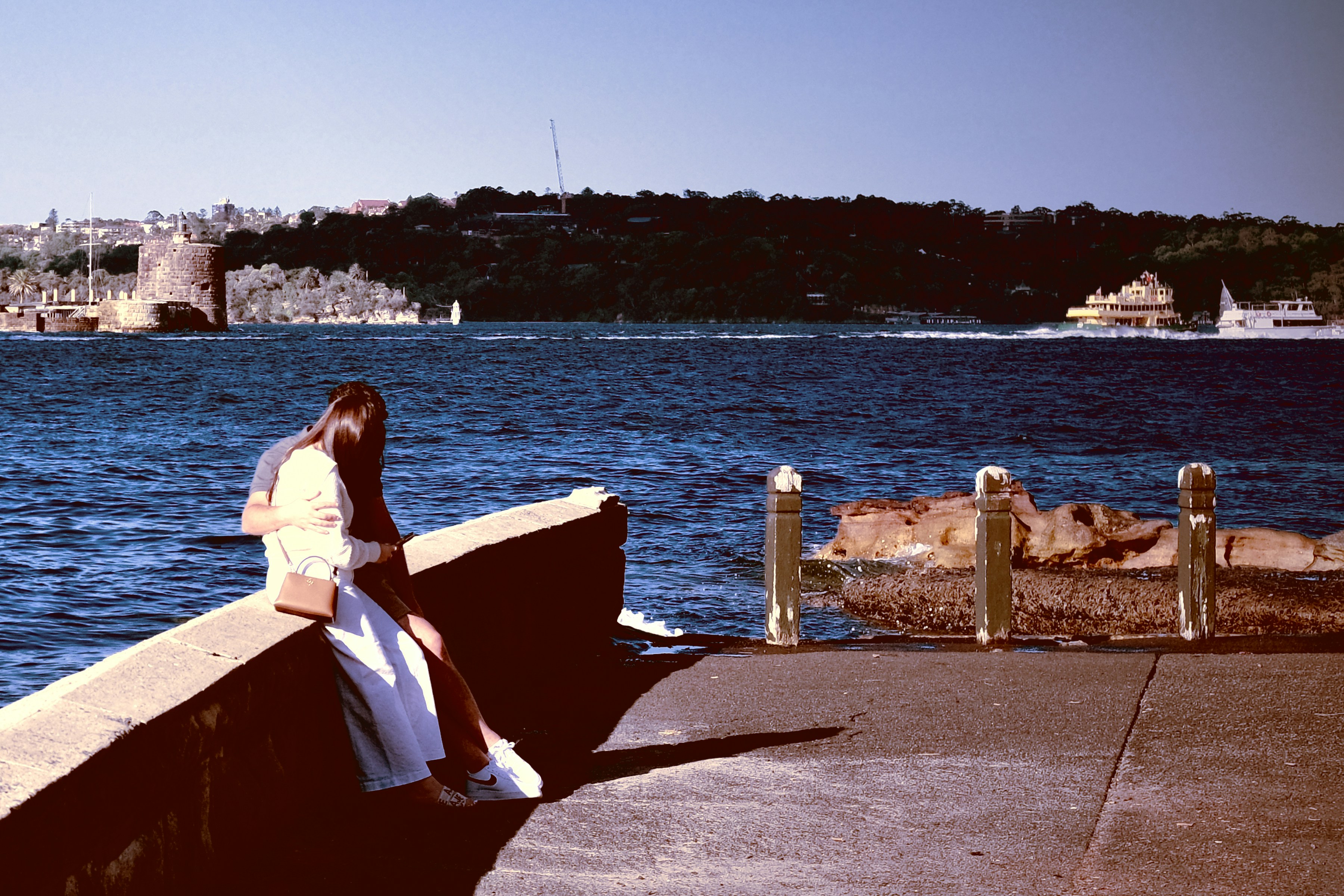 Seated figure at the waterfront: quiet moment by the harbor wall