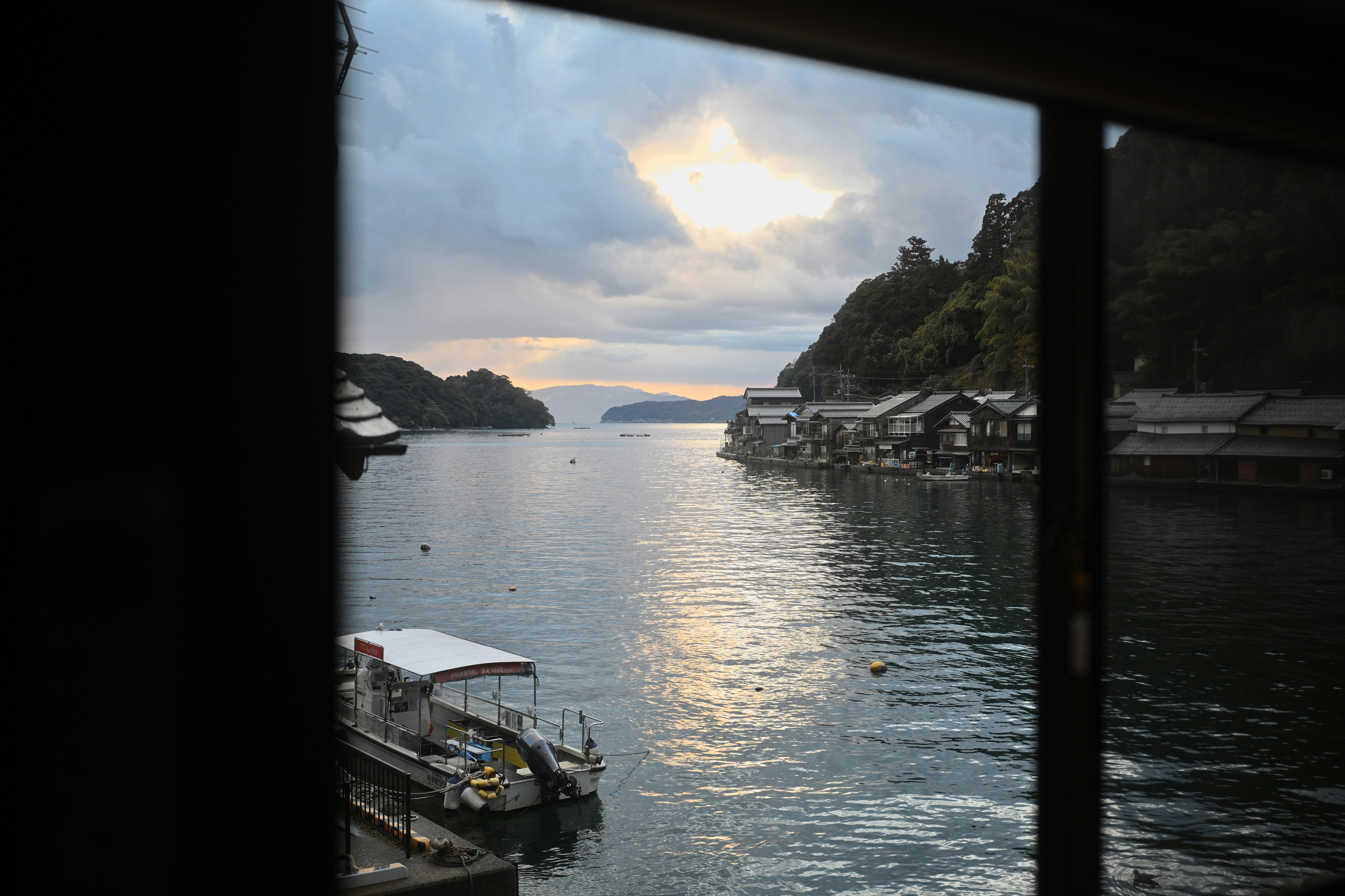 Harbor at Dusk: Boats, Houses, and Quiet Water Framed by Window Shutters