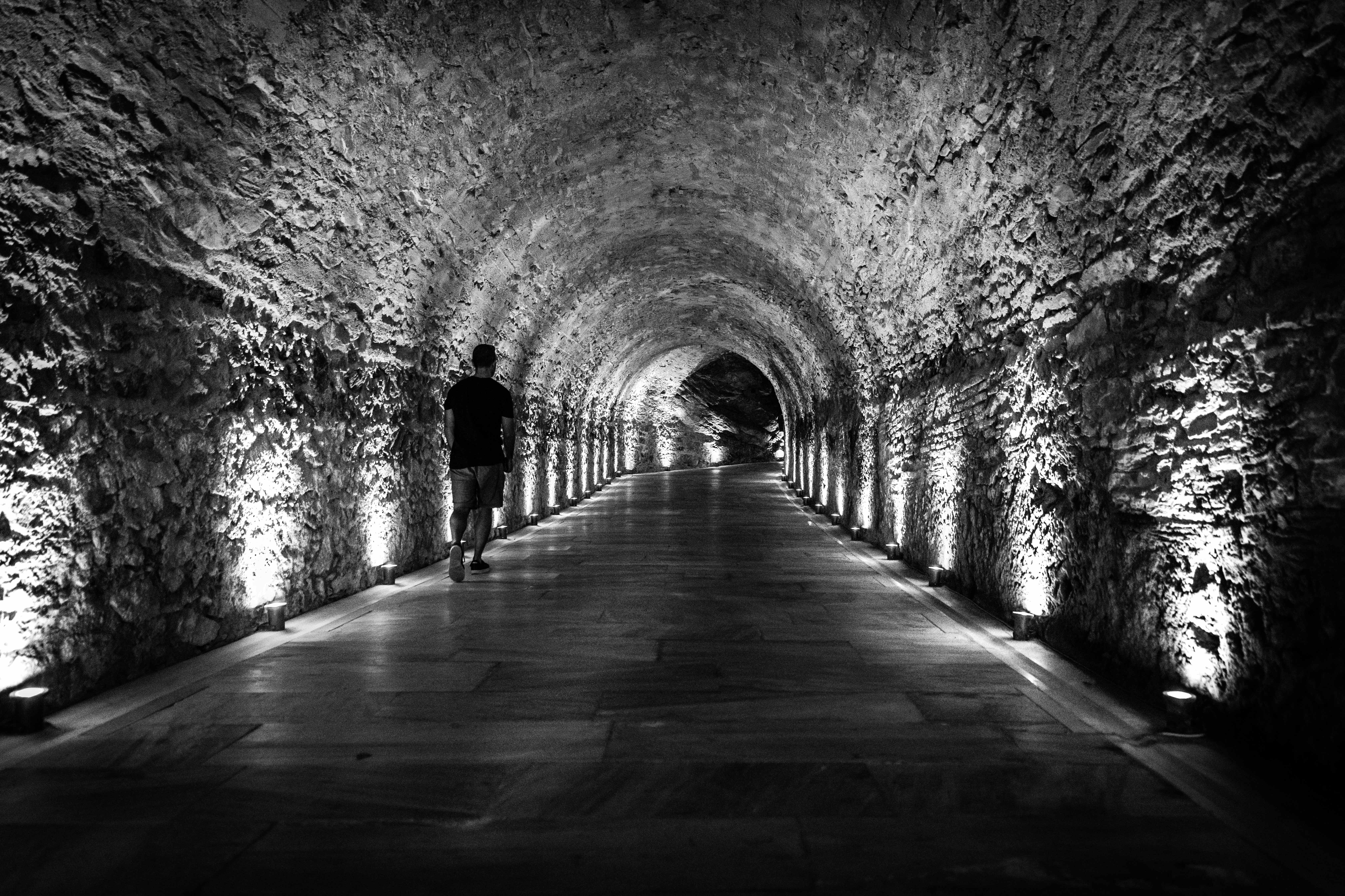Echoes of the Archway: A lone wanderer in a dim stone tunnel