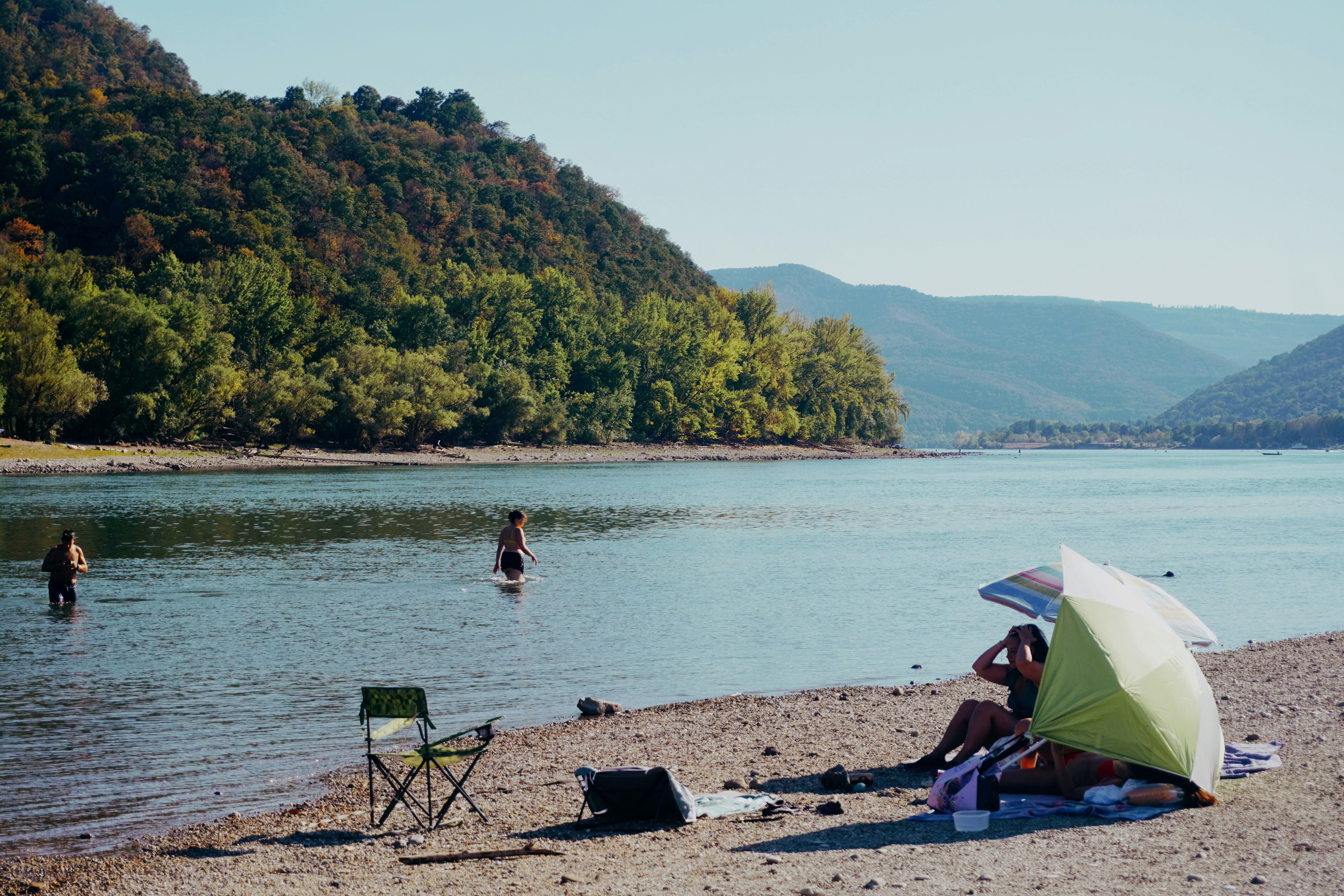Shoreline Retreat: People and Shade at a Quiet Lakeside Beach