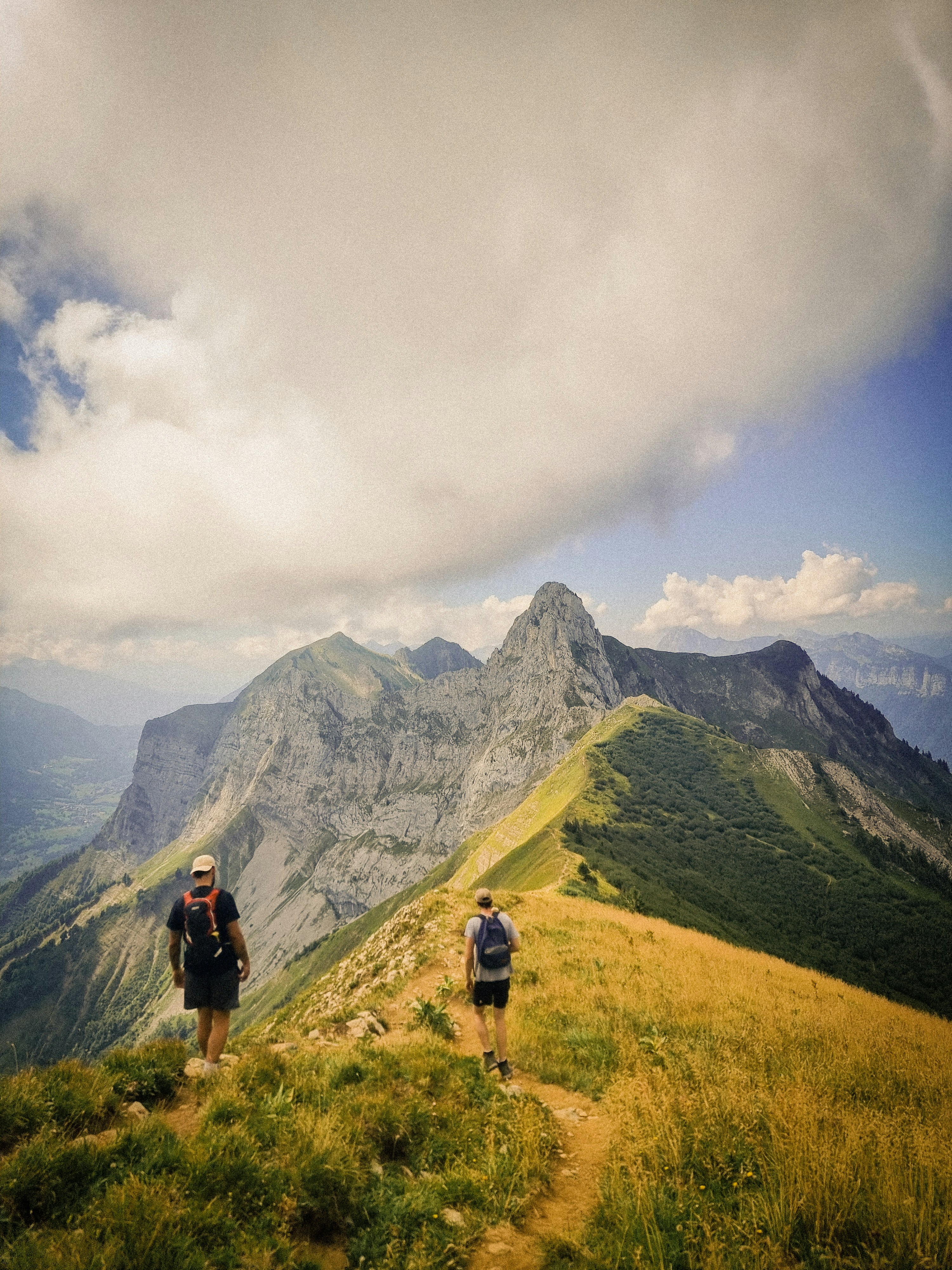 Trail to the Peak: Two hikers on a ridge under dramatic skies