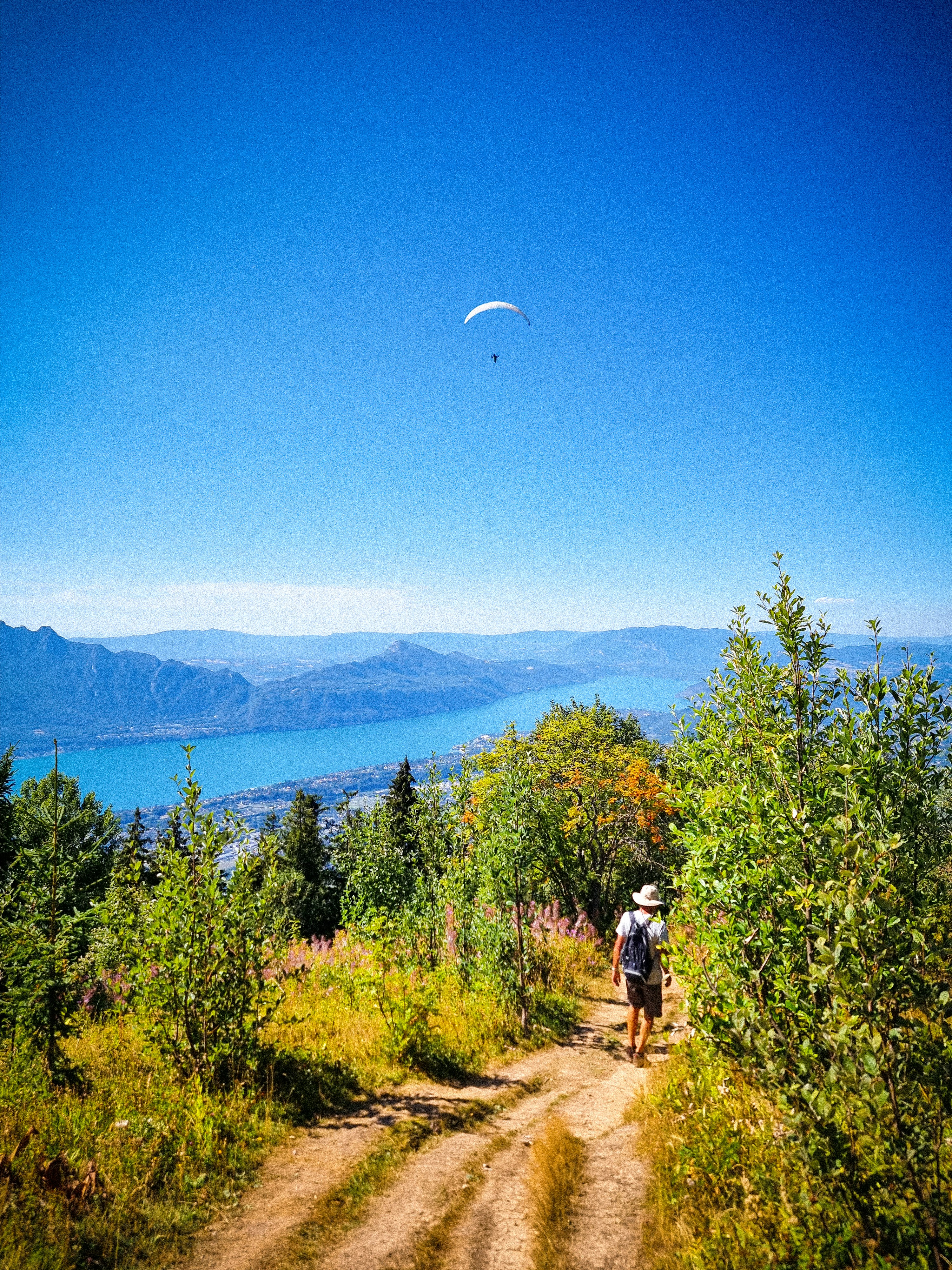 Trail to the Sky: Paraglider Above a Sunlit Lake