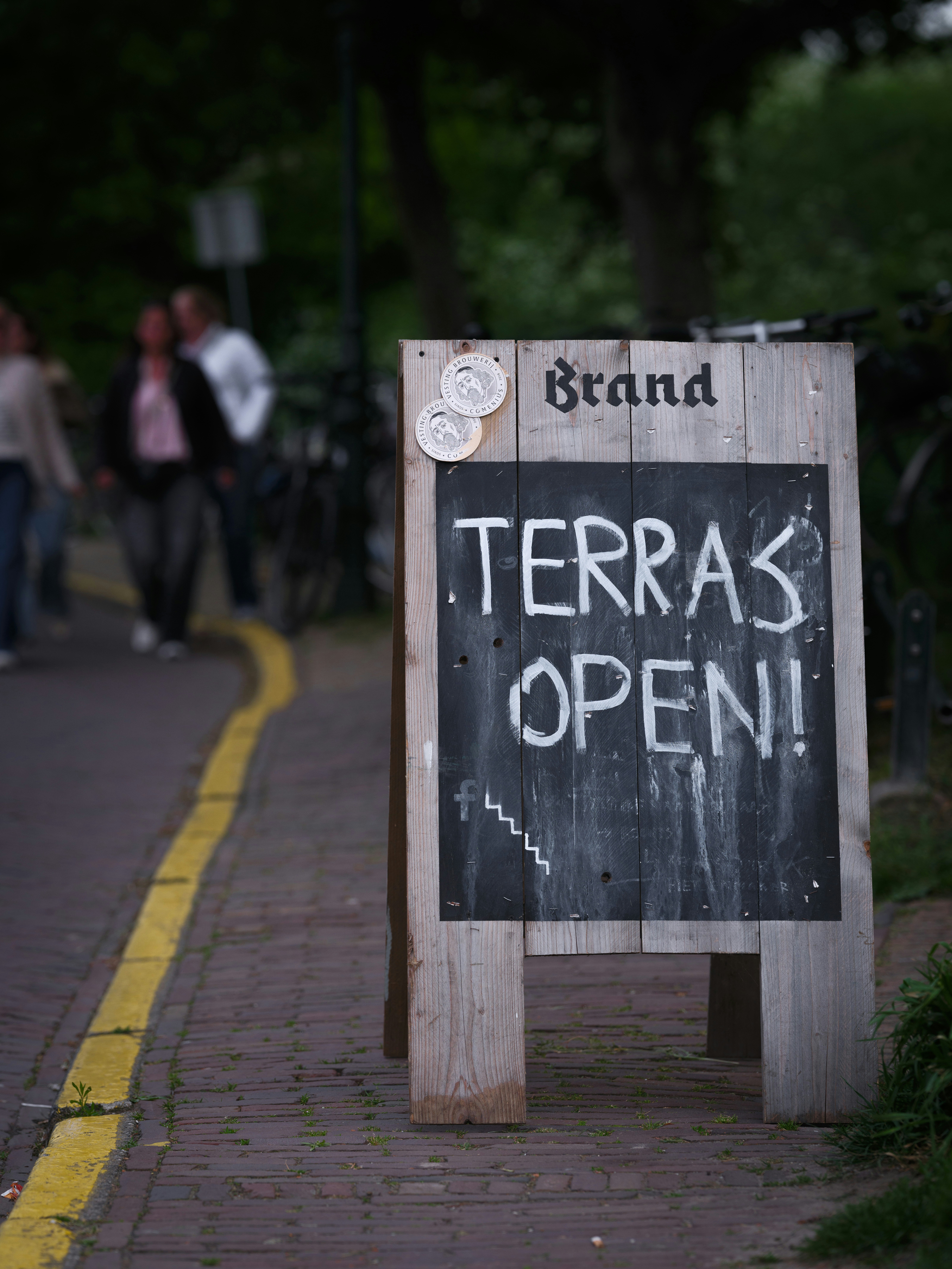 Chalkboard Sign in a Quiet City Walkway Opens a Street Café Scene