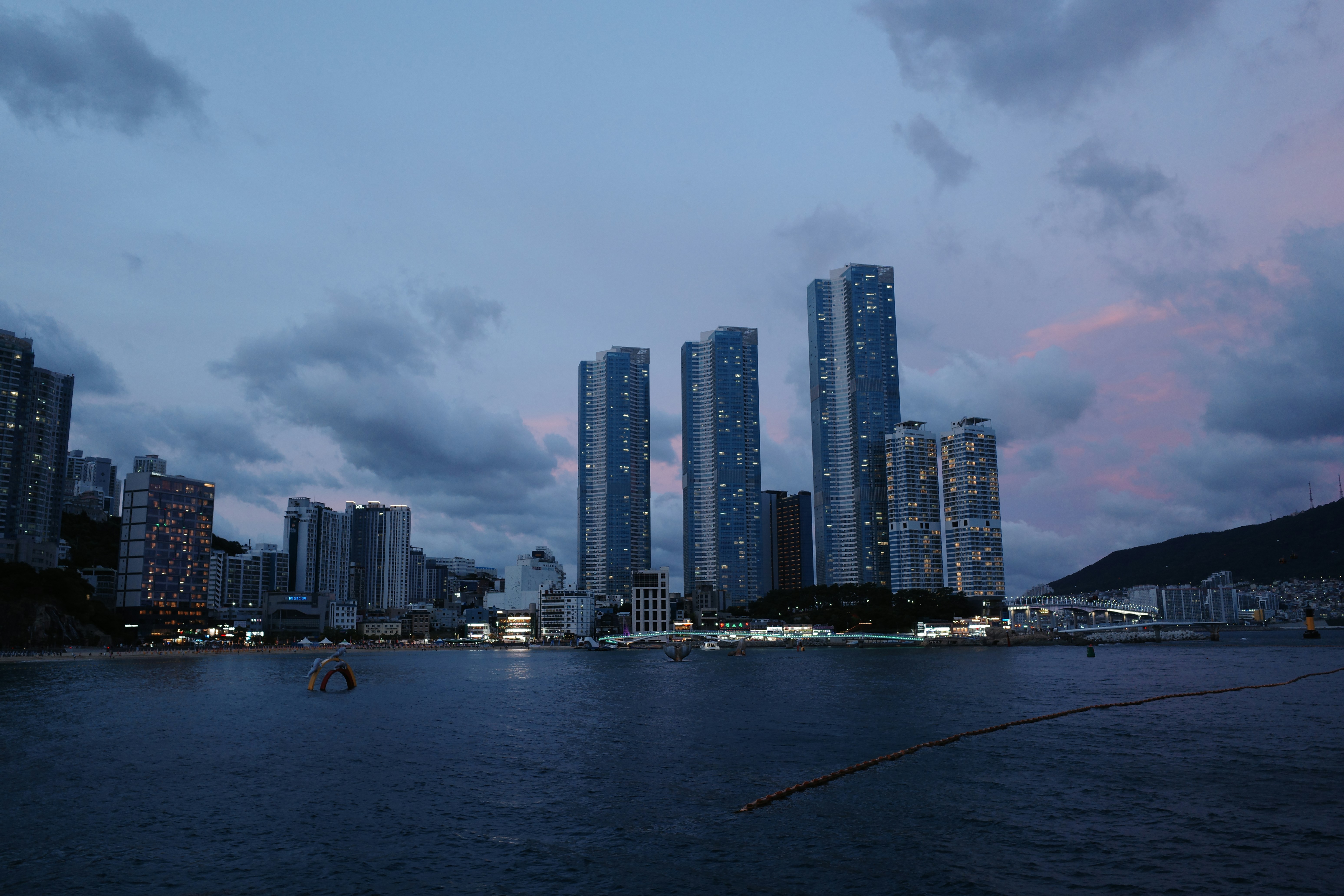 Urban Skyline at Dusk: City Glows Over Calm Waters