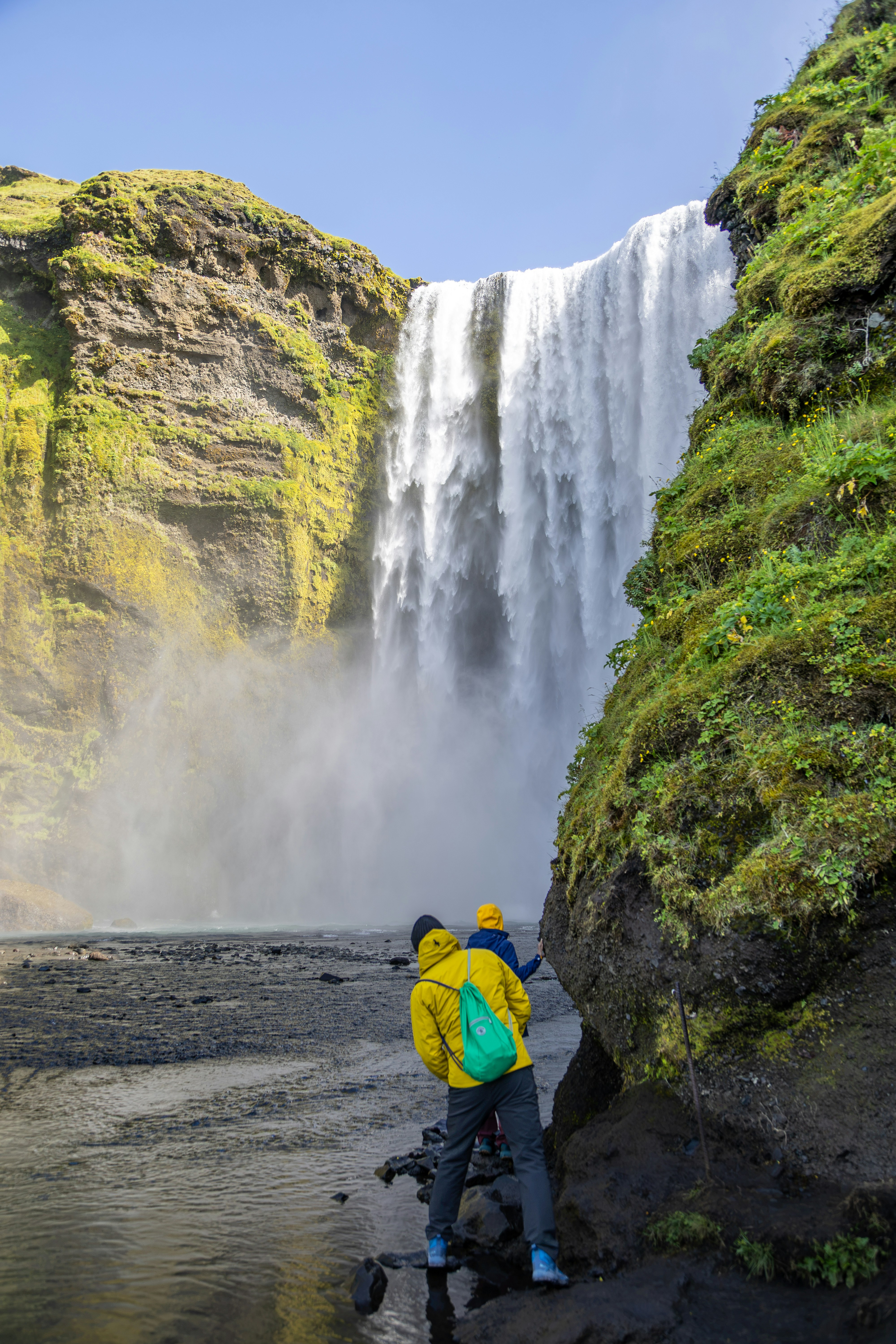 Hikers at the Edge: Green cliffs and a roaring waterfall