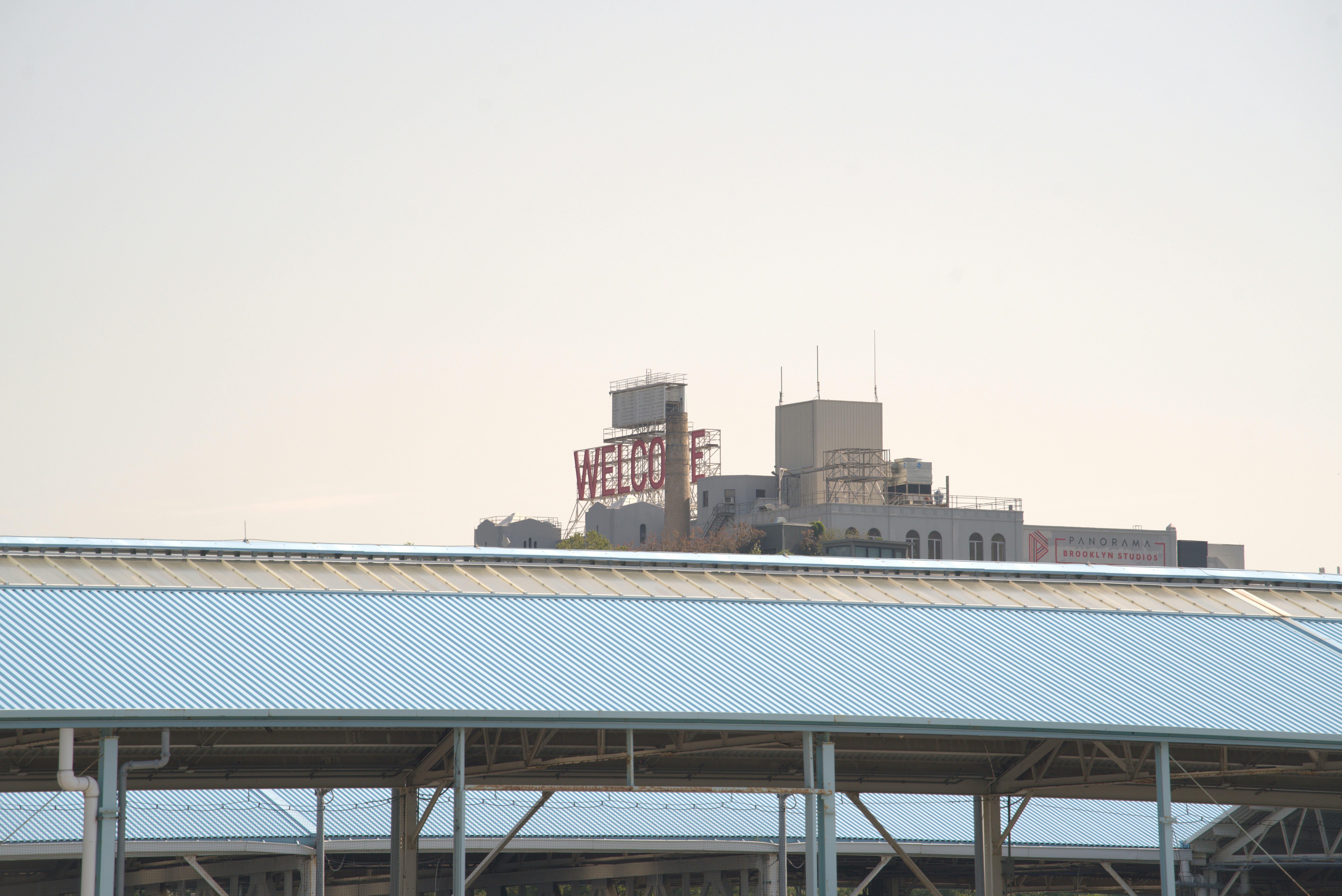 Welcome Sign Over a Distant Industrial Rooftop