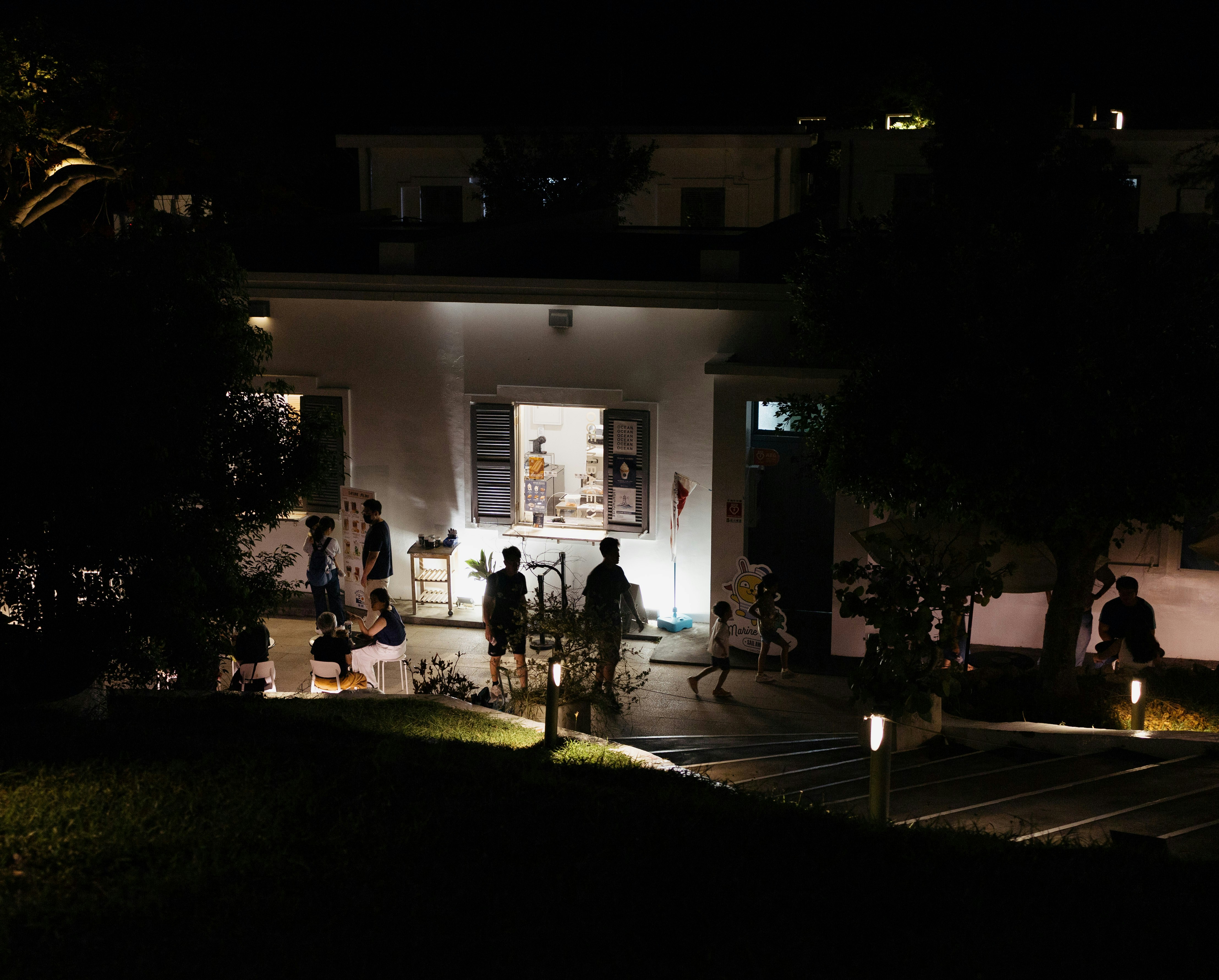 Night at the Quiet Courtyard: People Gather by a Small Building